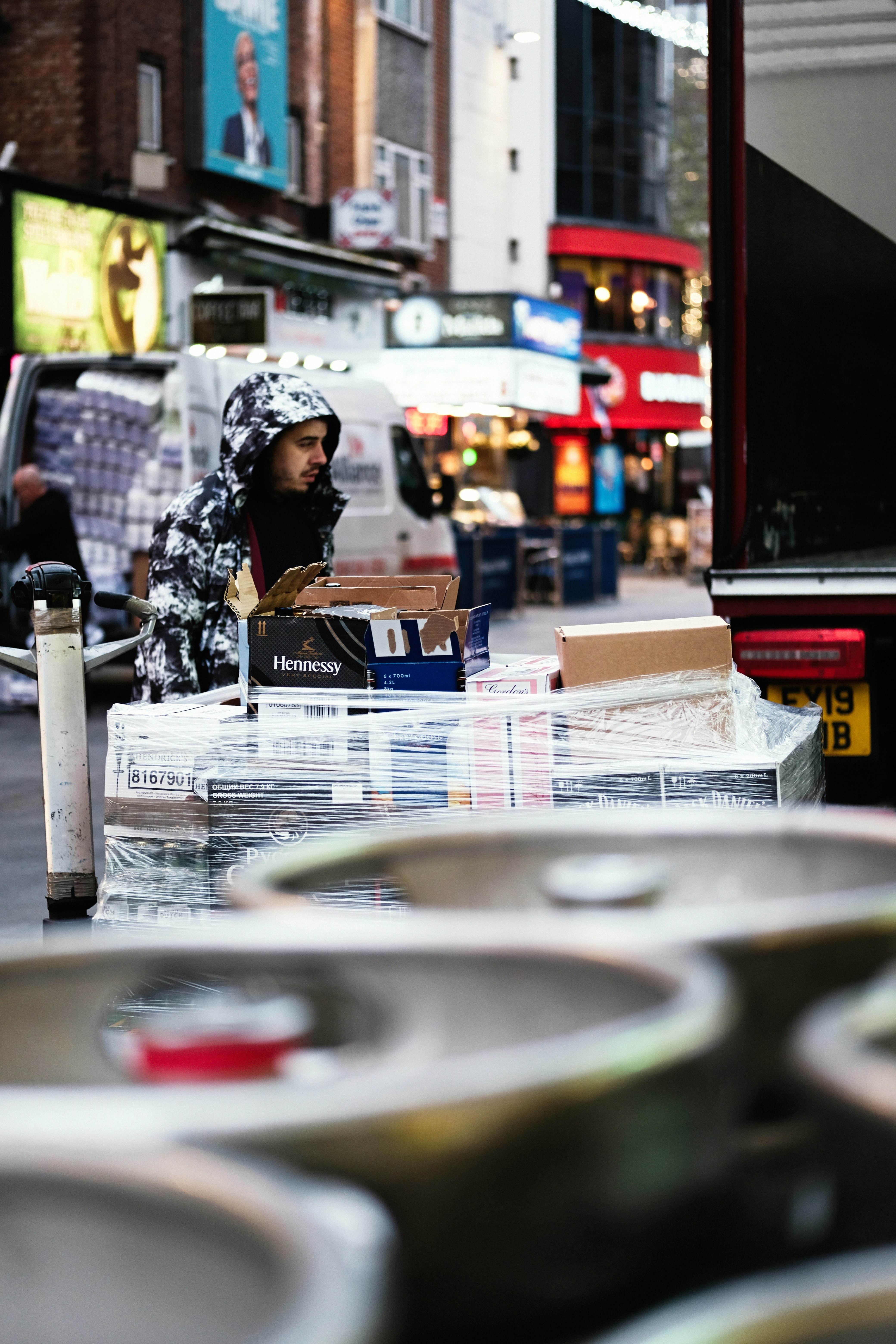 Hooded Vendor in a Street Market Surrounded by Crates
