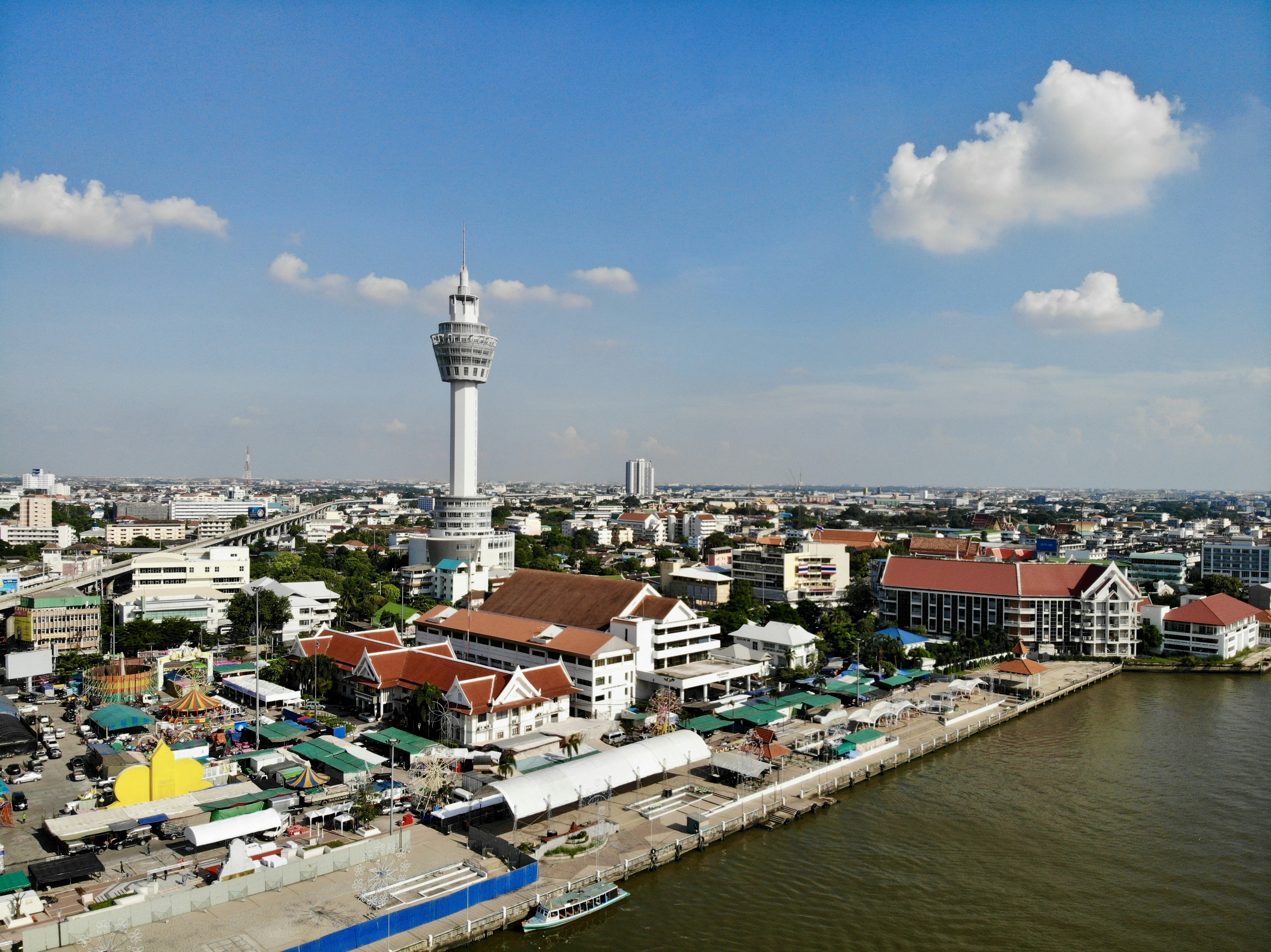 Aerial view of a bustling city with a prominent tower, showcasing a blend of modern architecture and waterfront activity.