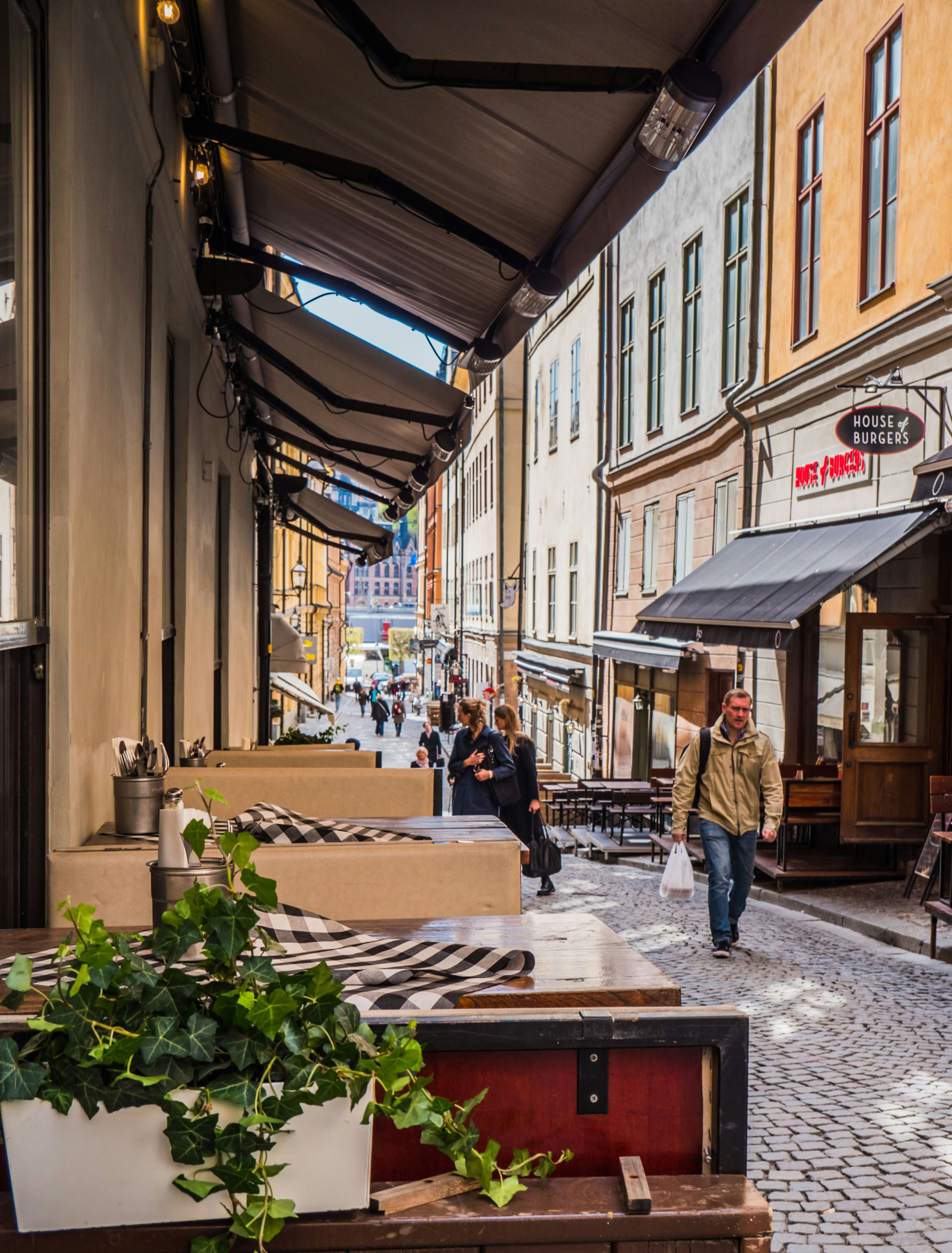 Stride Through the Sunlit Cobblestones: A Café-Lined Alley in Motion