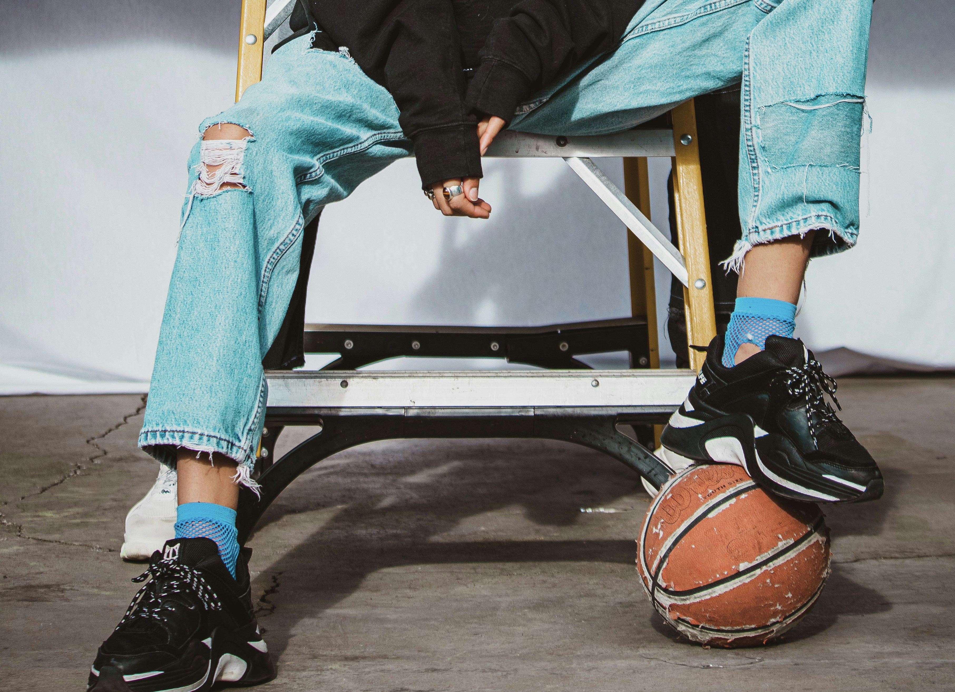 Person sitting on chair while stepping on orange basketball photo ...