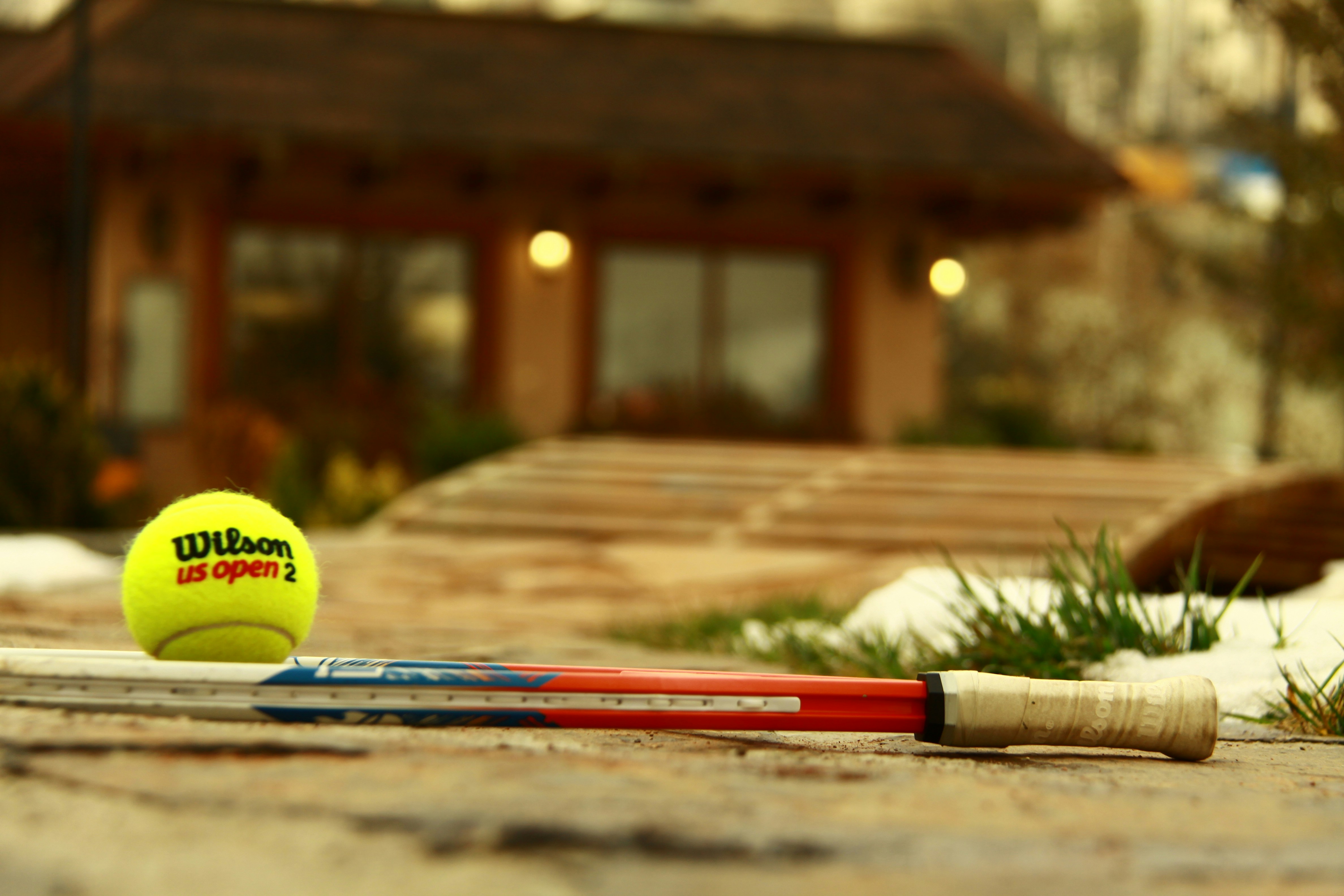 A tennis racket and a tennis ball on the ground photo – Free Brown ...