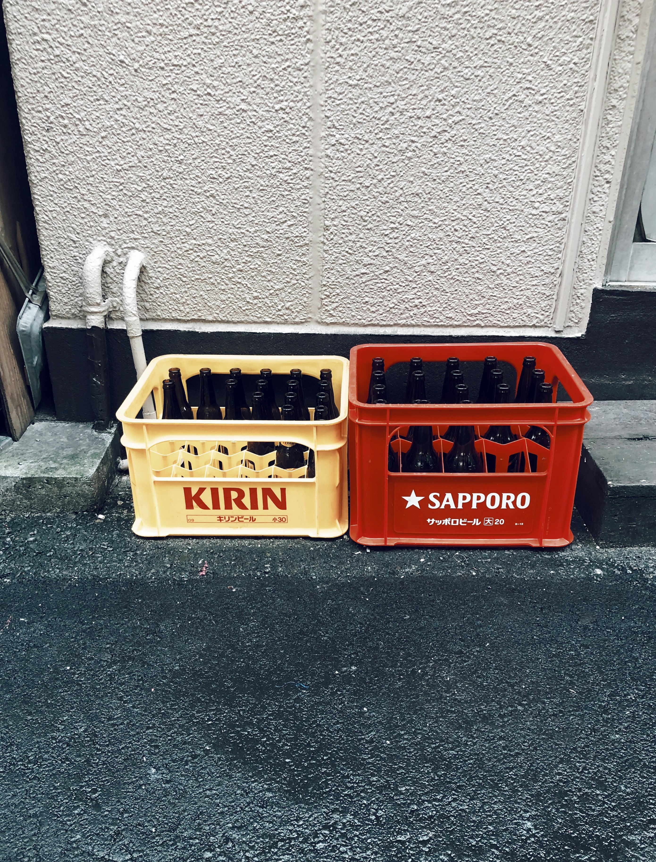 Crates of Kirin and Sapporo Rest on Rain-Worn Asphalt