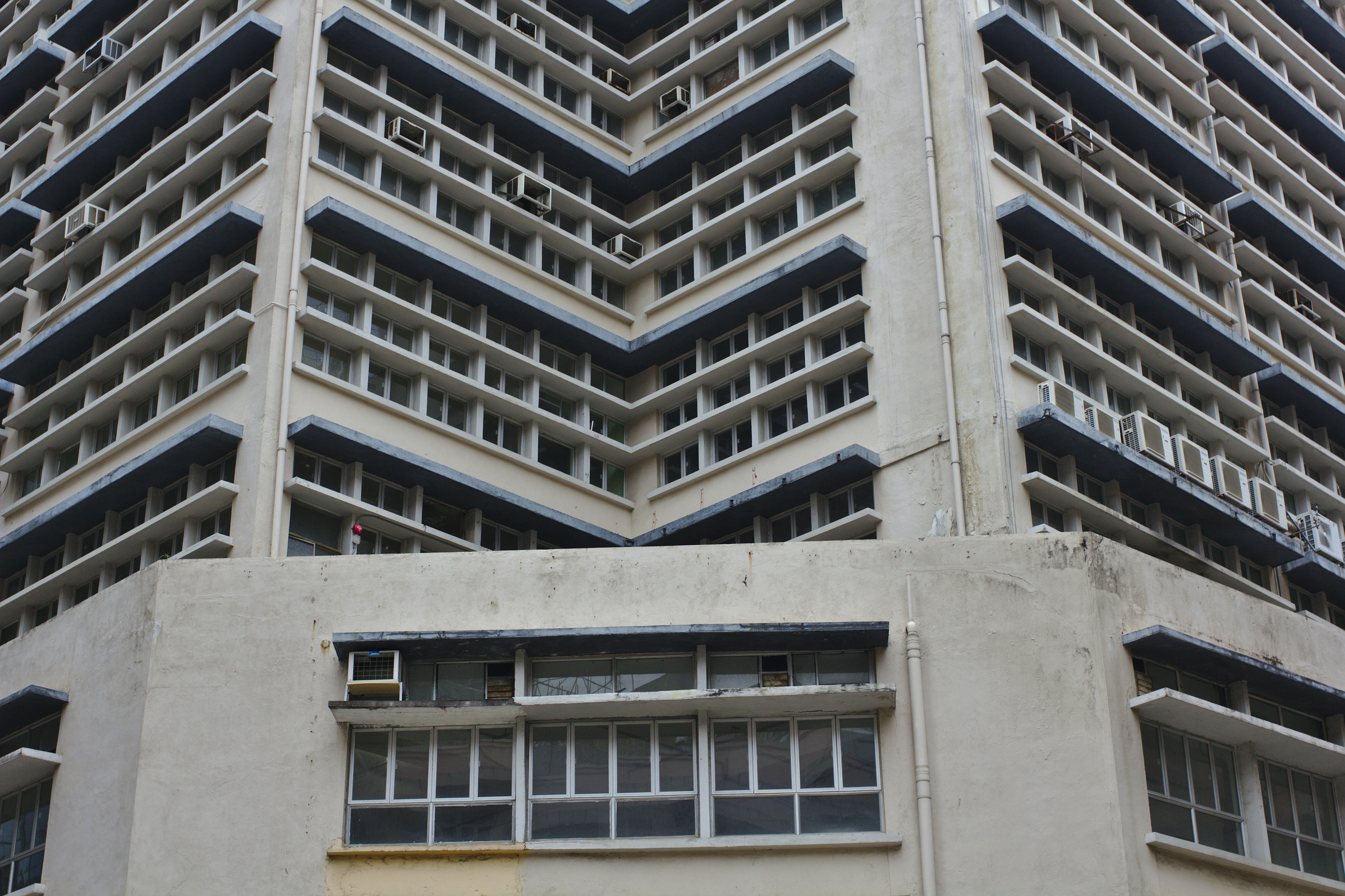 Angular façade of a multi-story building showcasing a rhythmic pattern of windows and balconies.