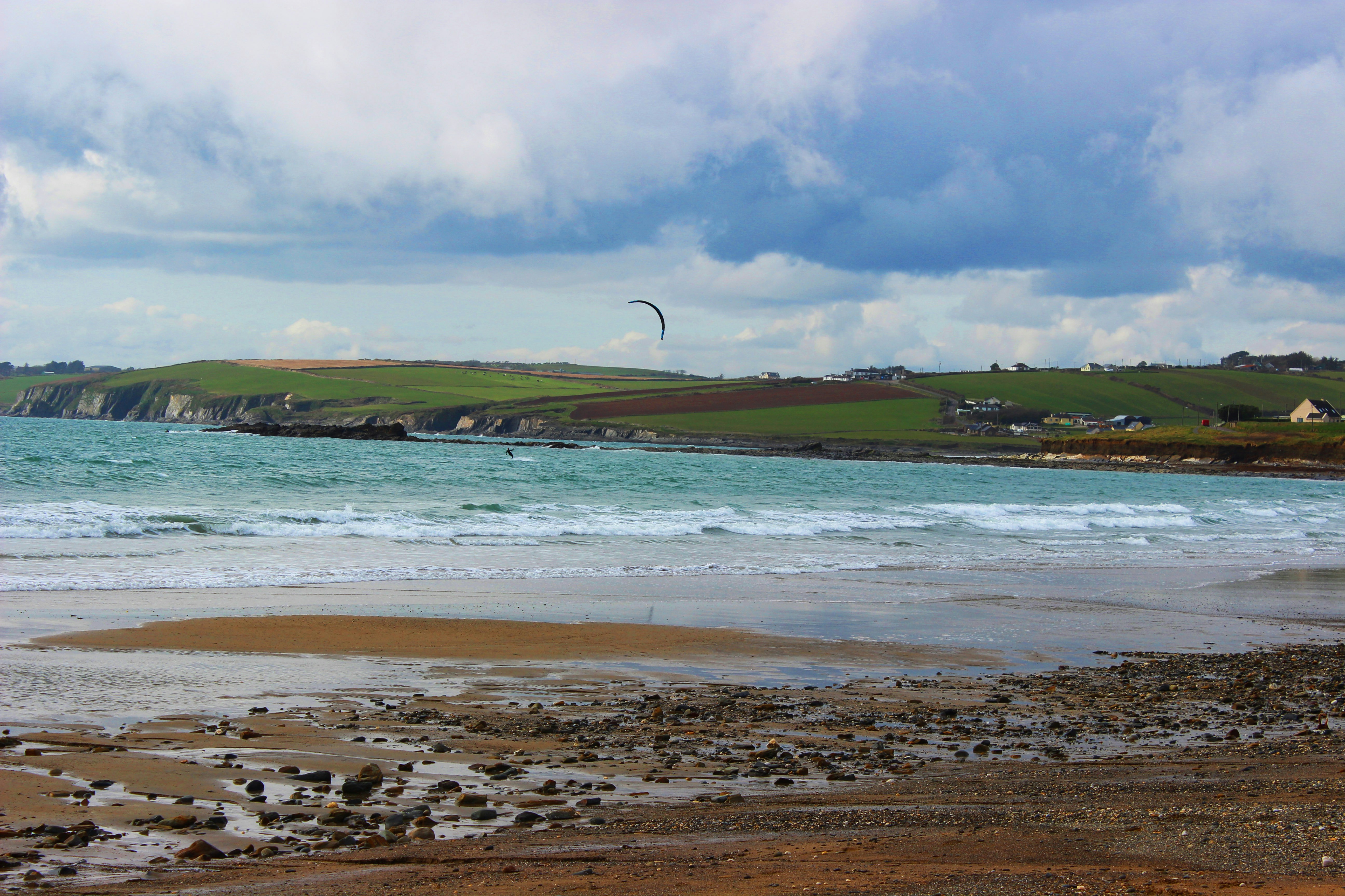 Paraglider's Silver Arc Over a Windswept Coast