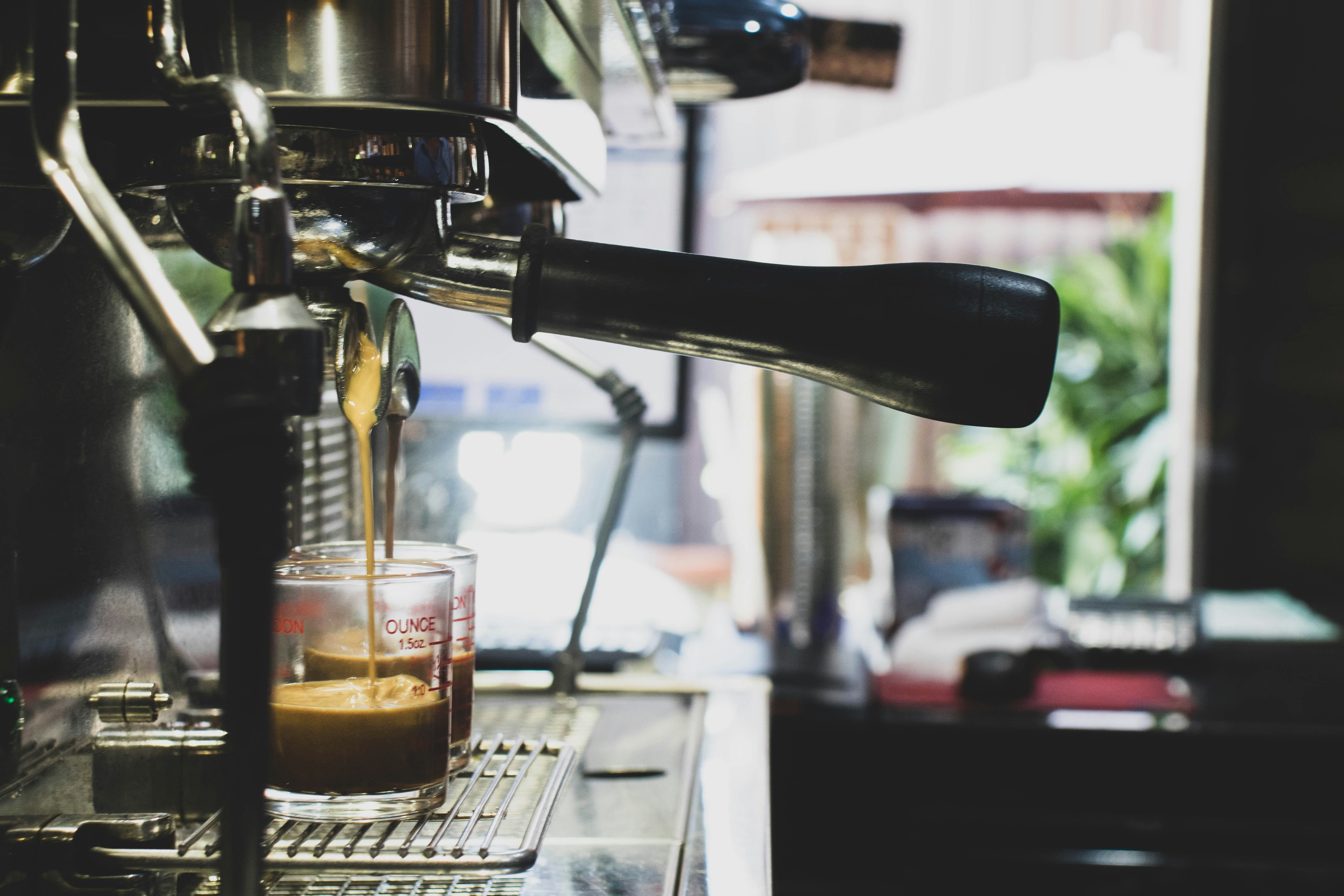 Espresso machine pouring coffee into a glass cup in a cozy cafe setting.