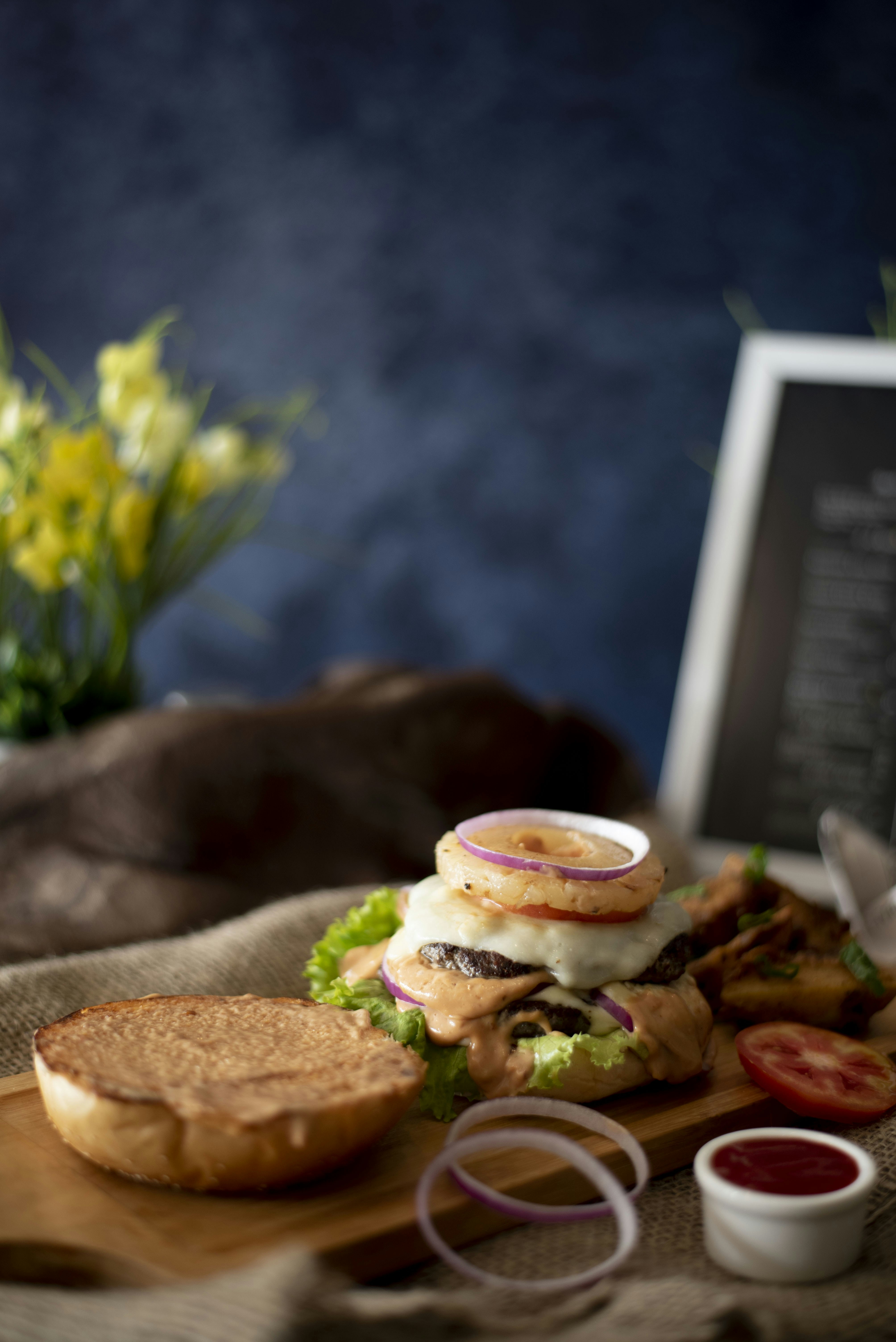 Layered Burger Portrait on a Rustic Board Against a Velvet-Blue Backdrop