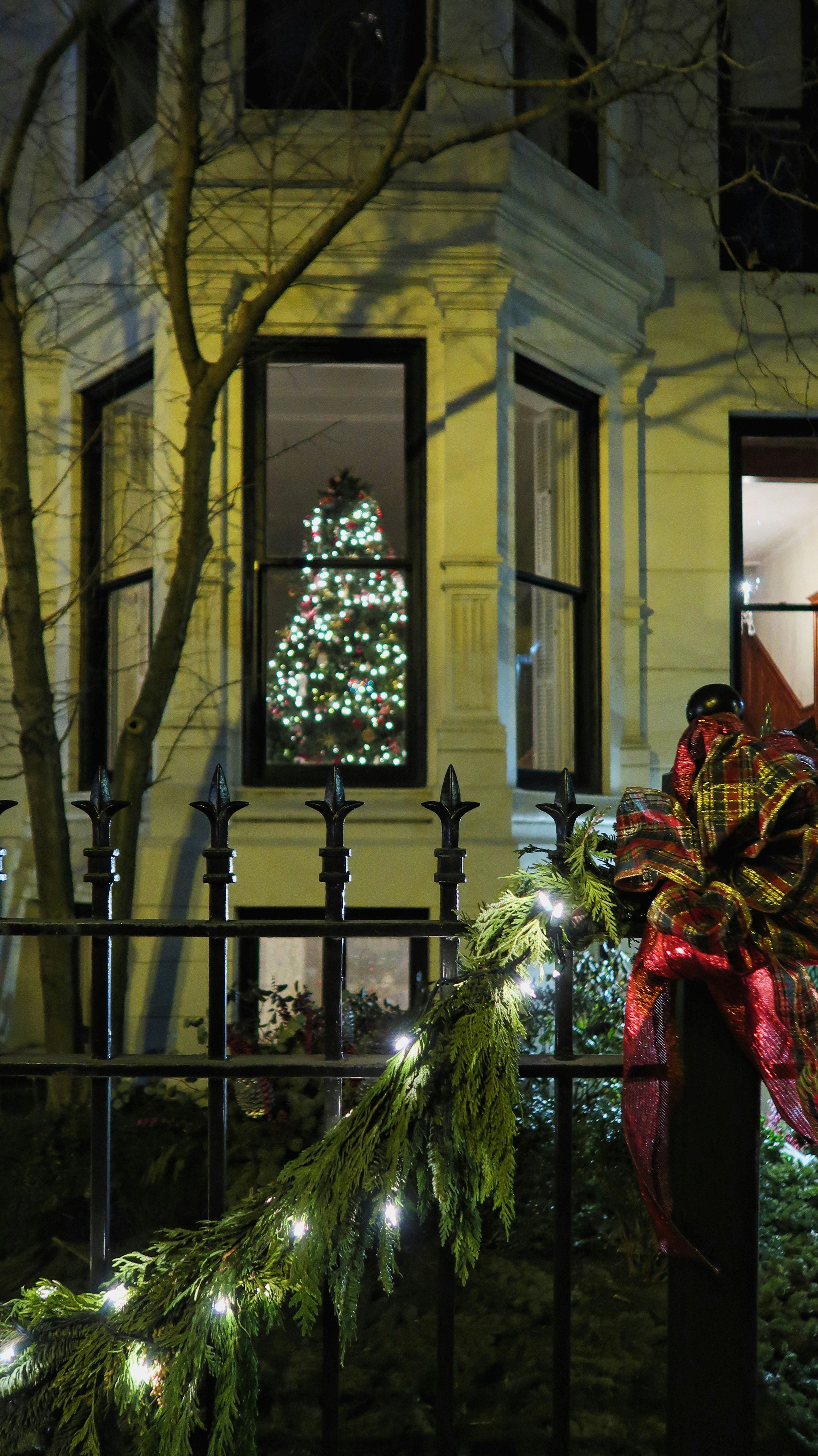 Yuletide Window: Christmas Lights Framed by an Iron Fence