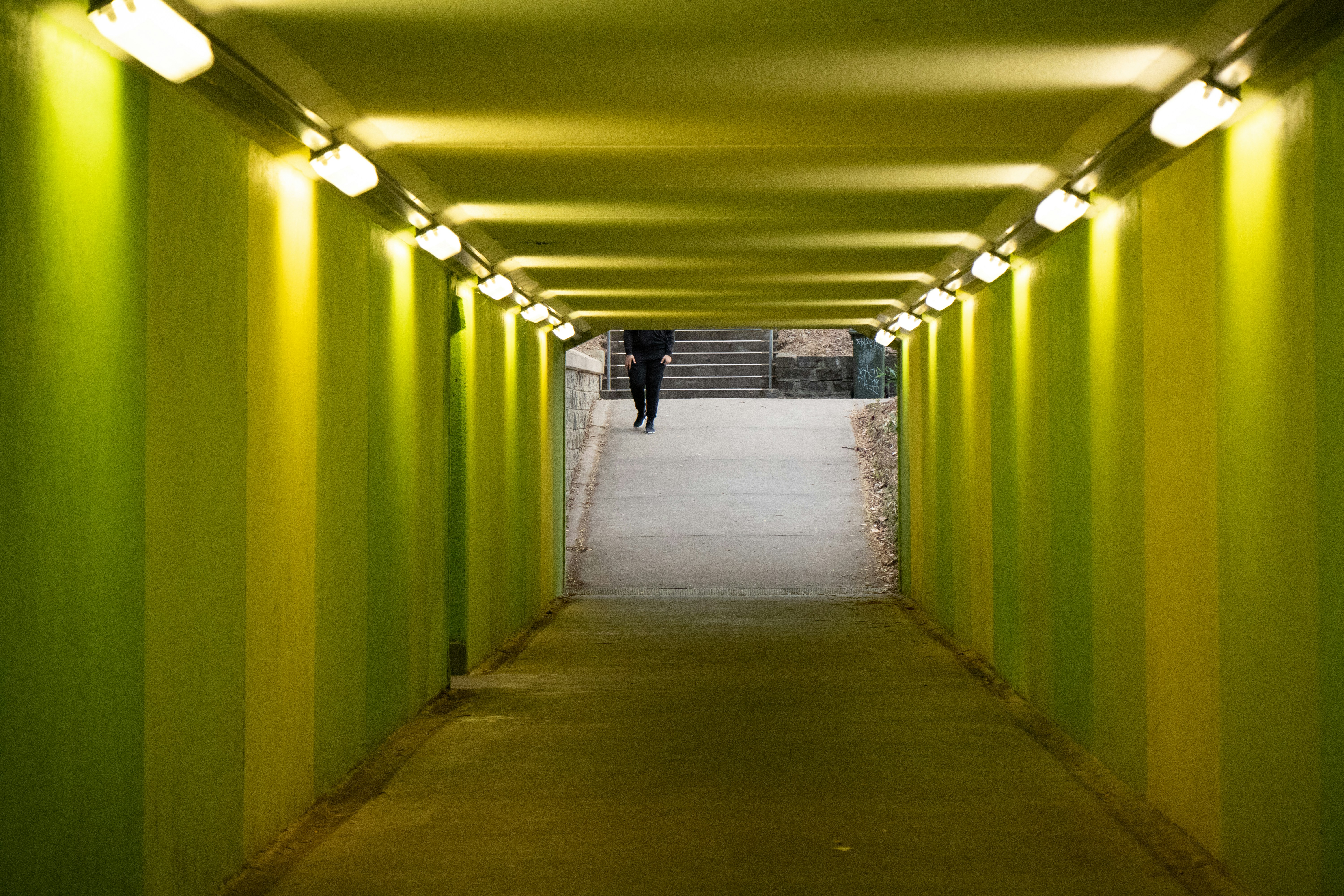 Lone Silhouette Emerges from a Lime-Green Underpass