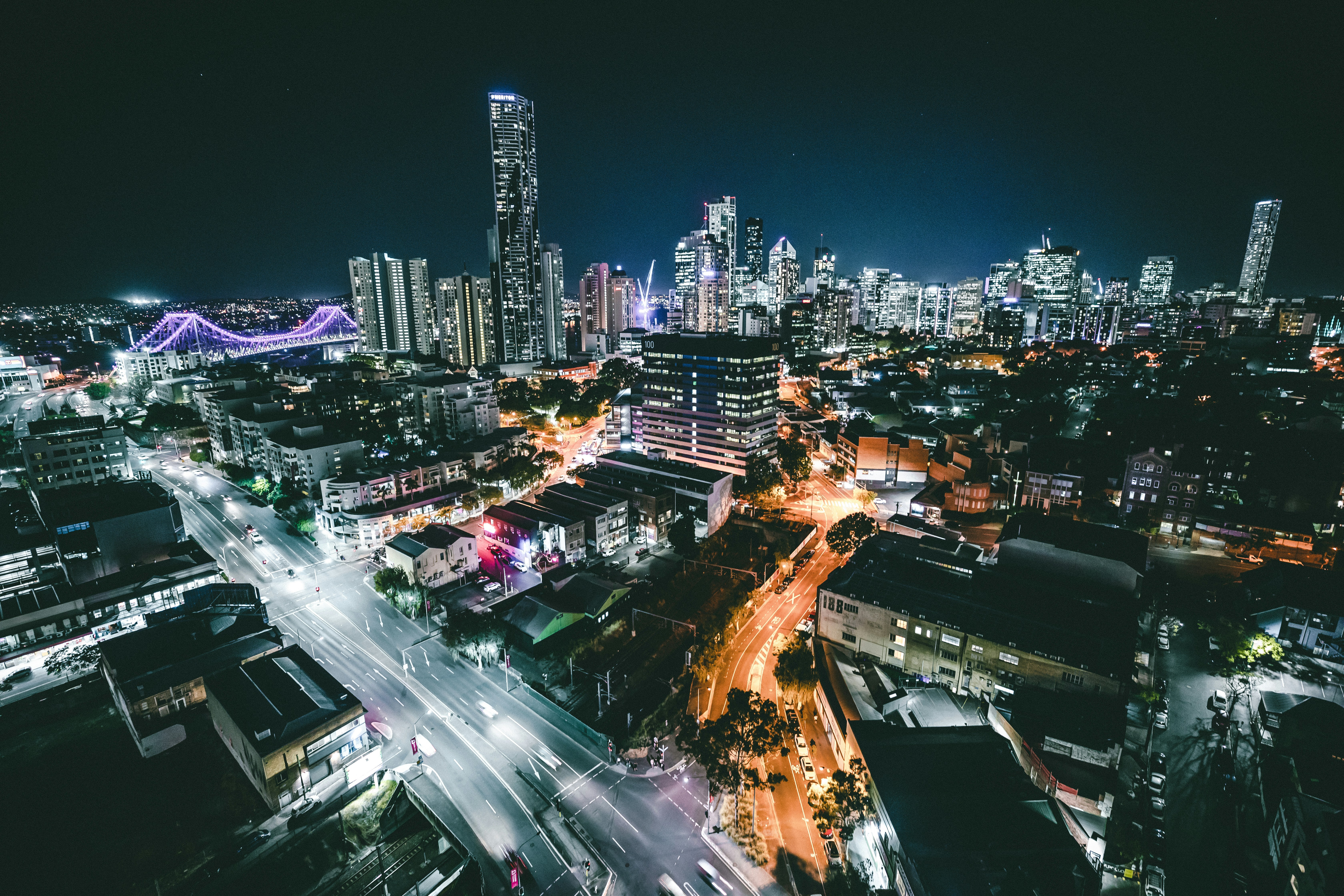 Vibrant cityscape with illuminated buildings and streets under a night sky.