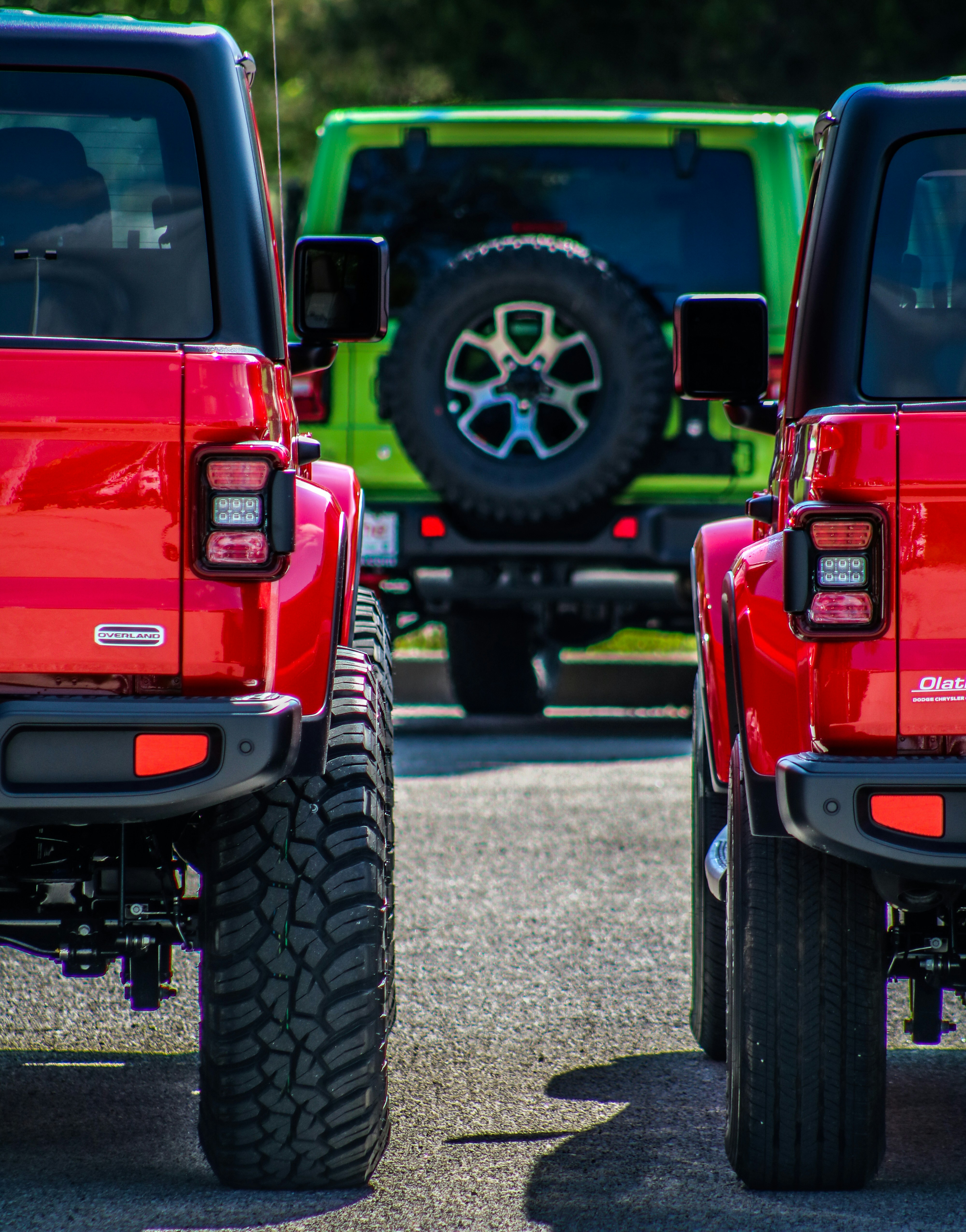 Green off-road vehicle in front of two red off-road vehicles photo ...