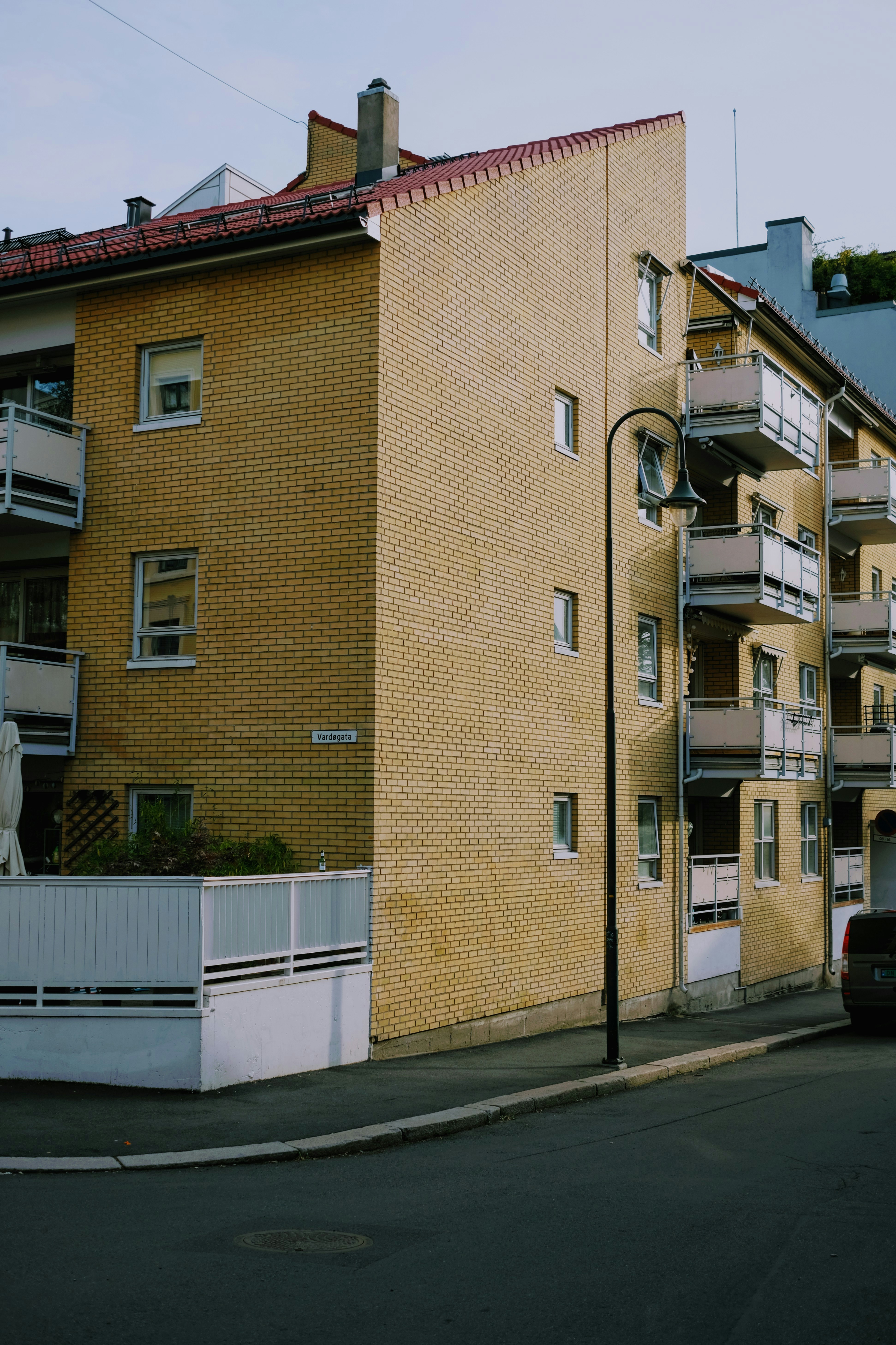 Yellow brick apartment building corner illuminated by soft afternoon light, highlighting architectural details and shadows.