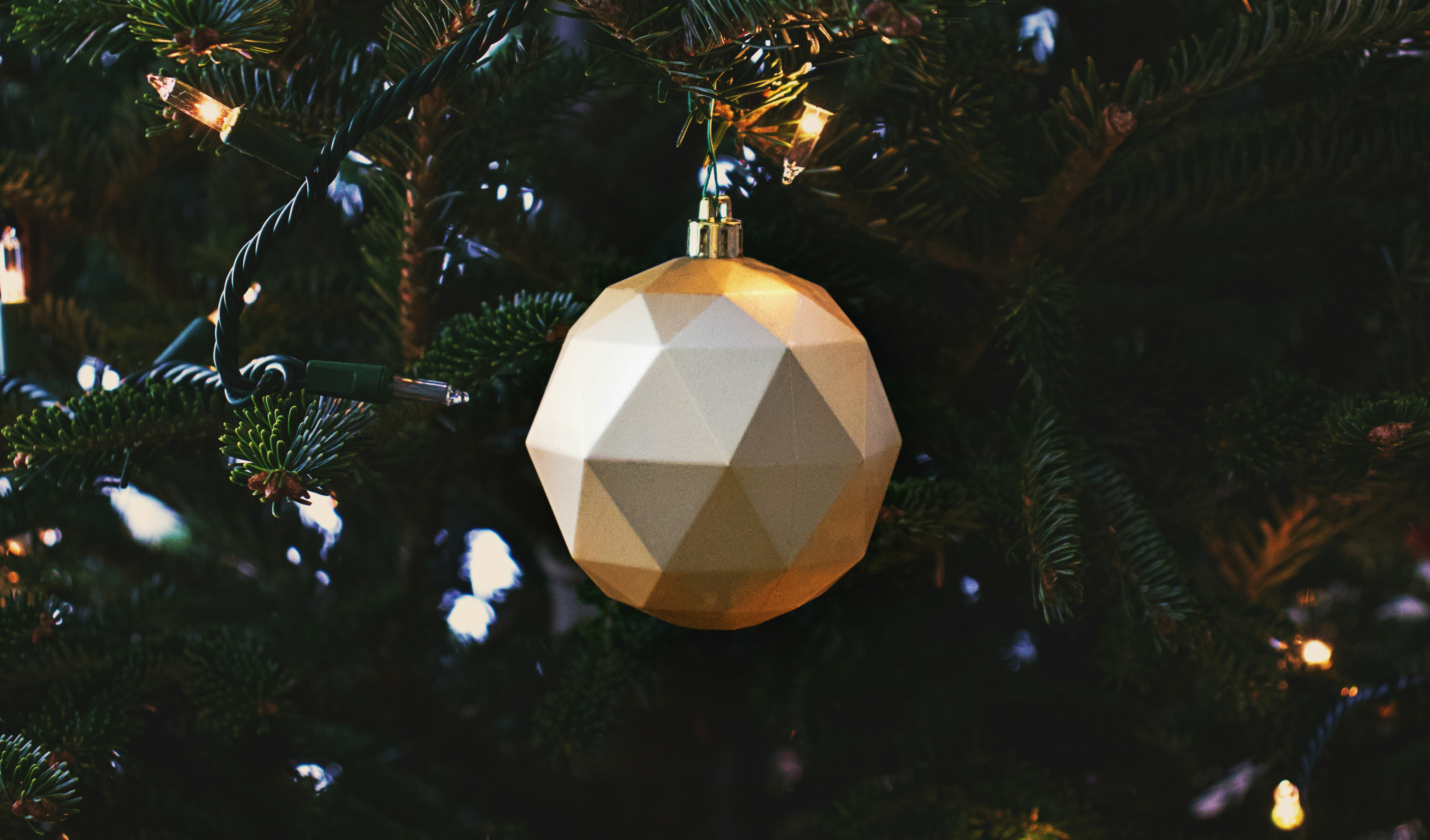Facet in Gold: A Geometric Christmas Ornament against Twinkling Lights