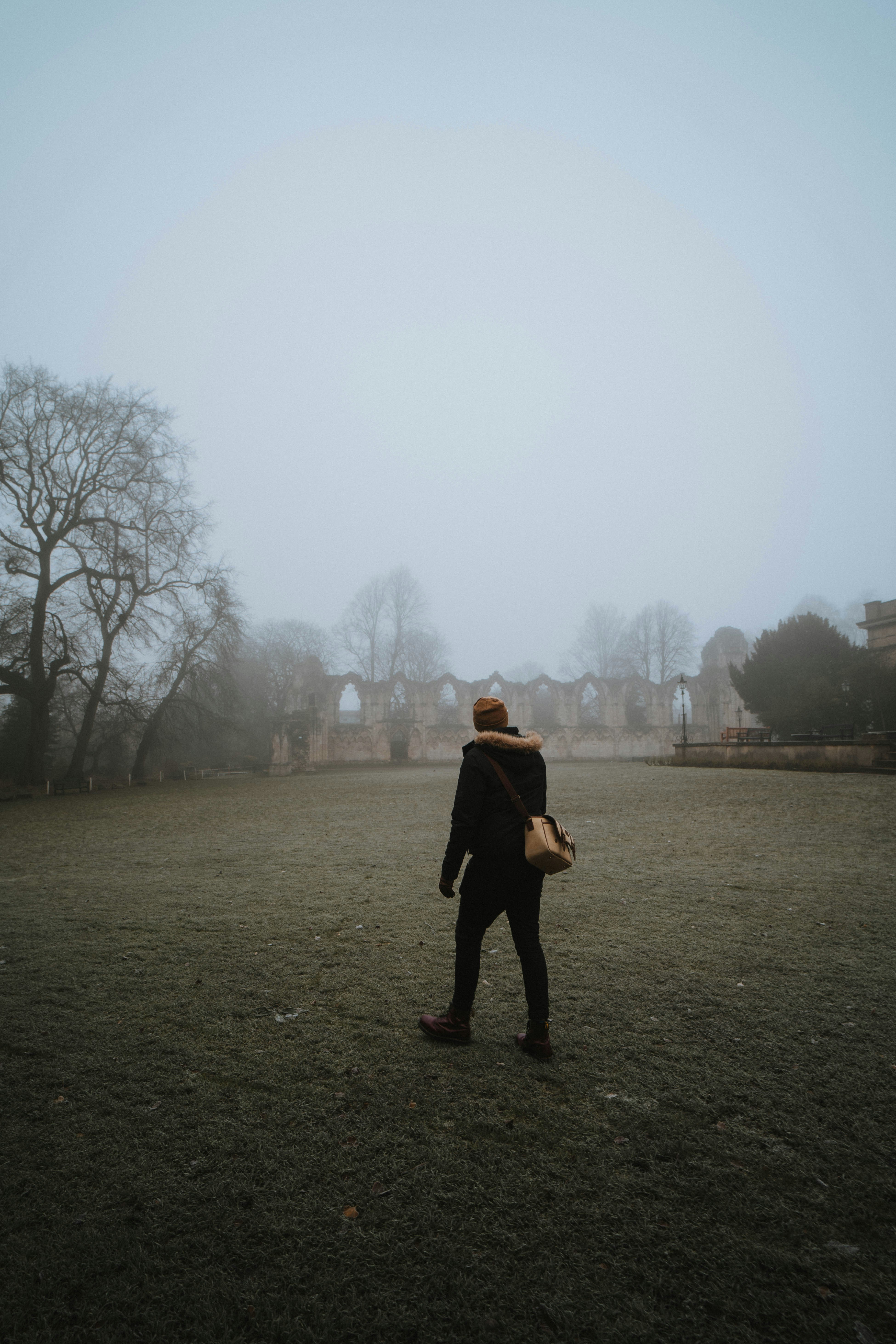 Fogbound Footsteps: A solitary wanderer in a misty ruin park