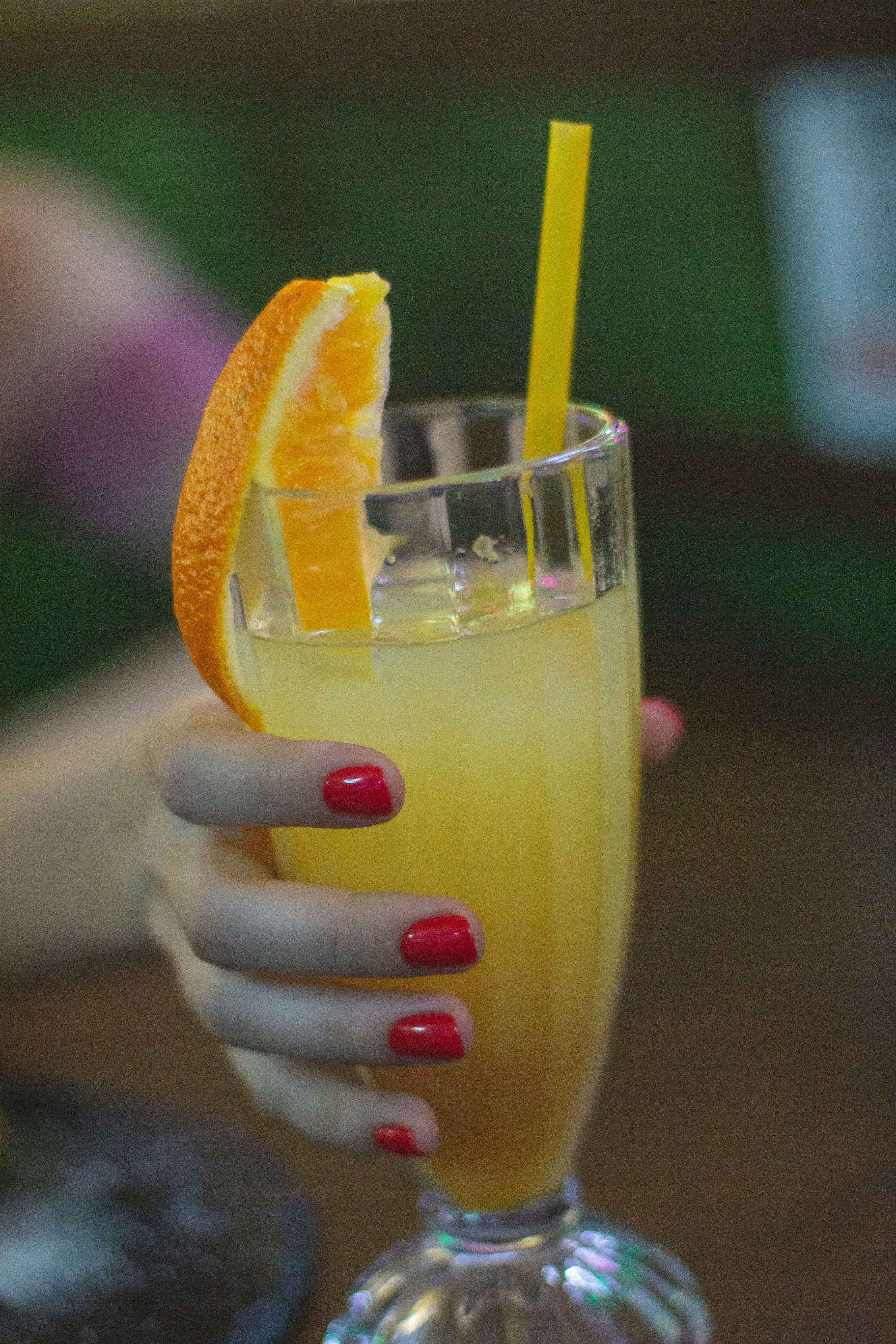 Crimson Nails, Citrus Glow: A Close-Up on a Sunny Glass