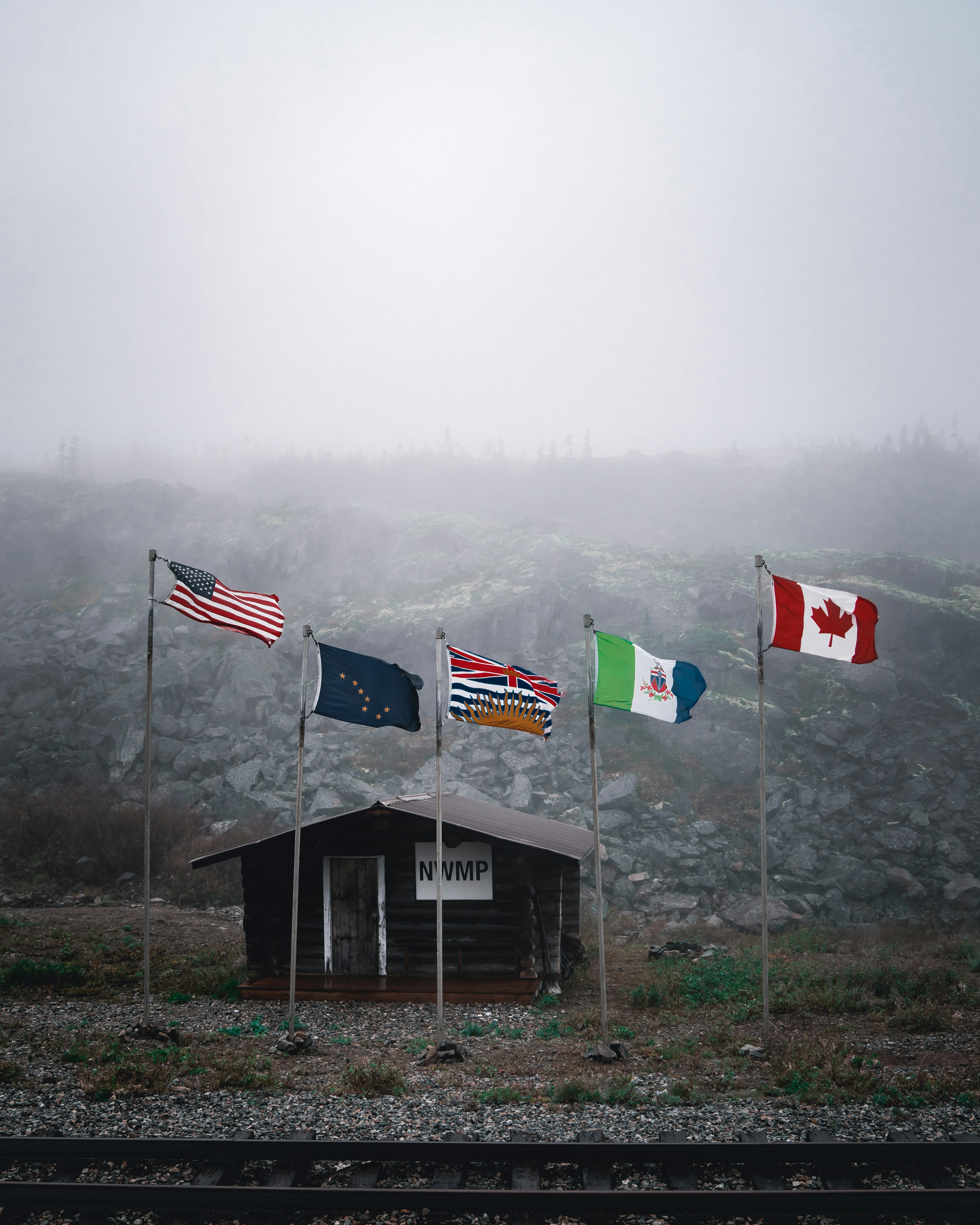 Five assorted flags on poles by cabin during foggy weather photo – Free ...