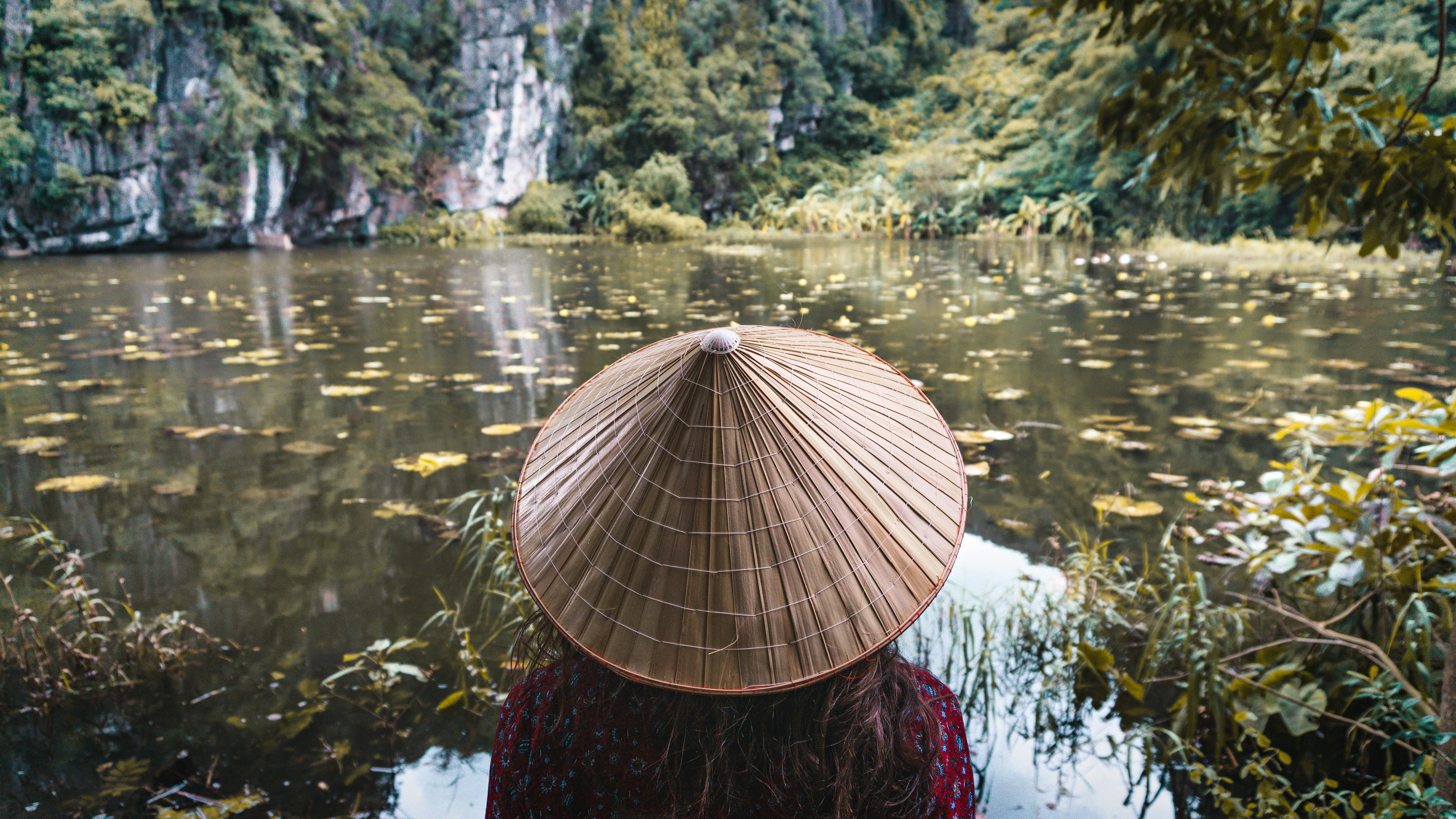 girl standing with a hat on at lake in Ninh Binh Vietnam Southeast Asia | woman wearing brown wicker hat