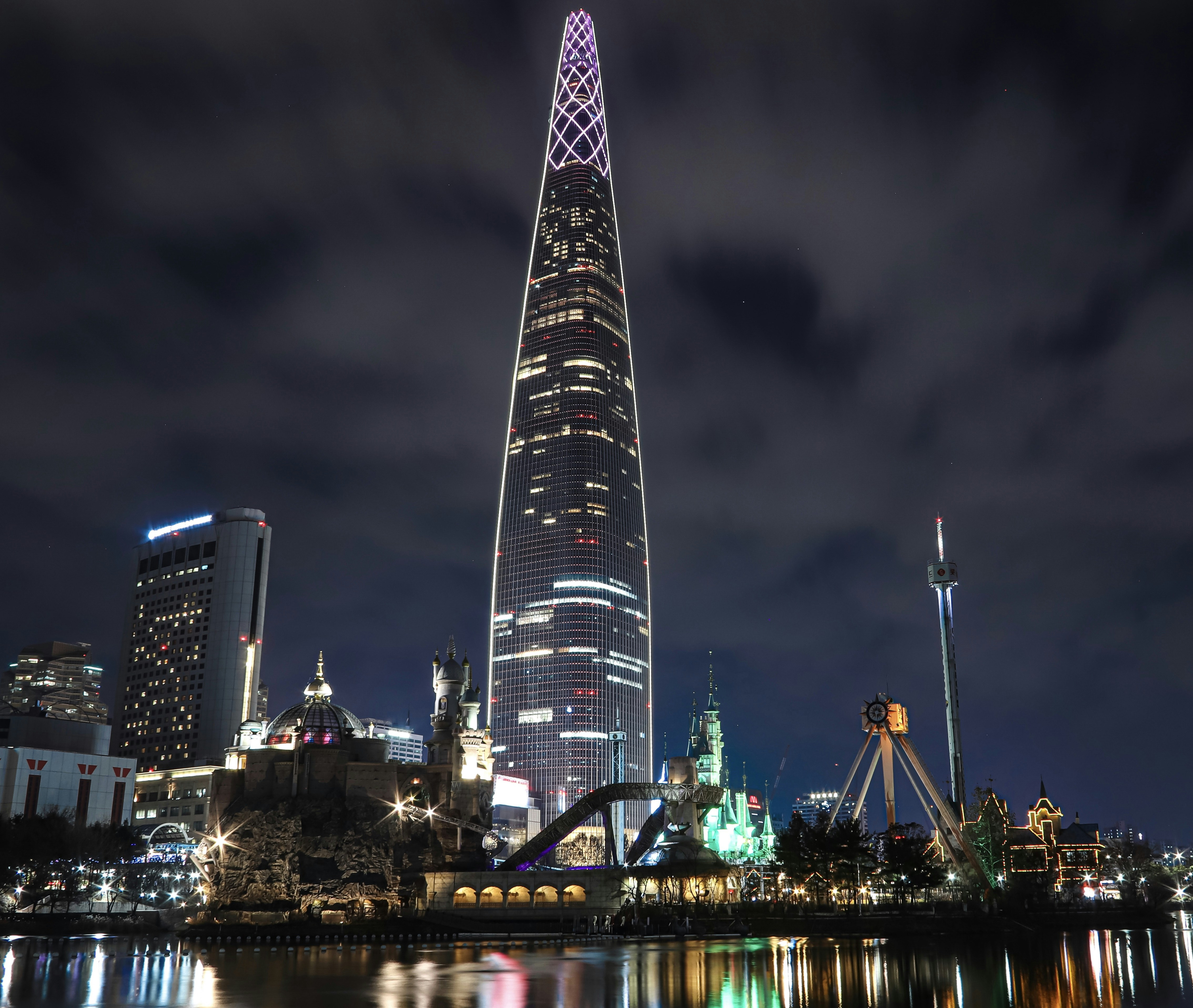 Lattice-Topped Spire Lit by Night: Neon Reflections Over the River