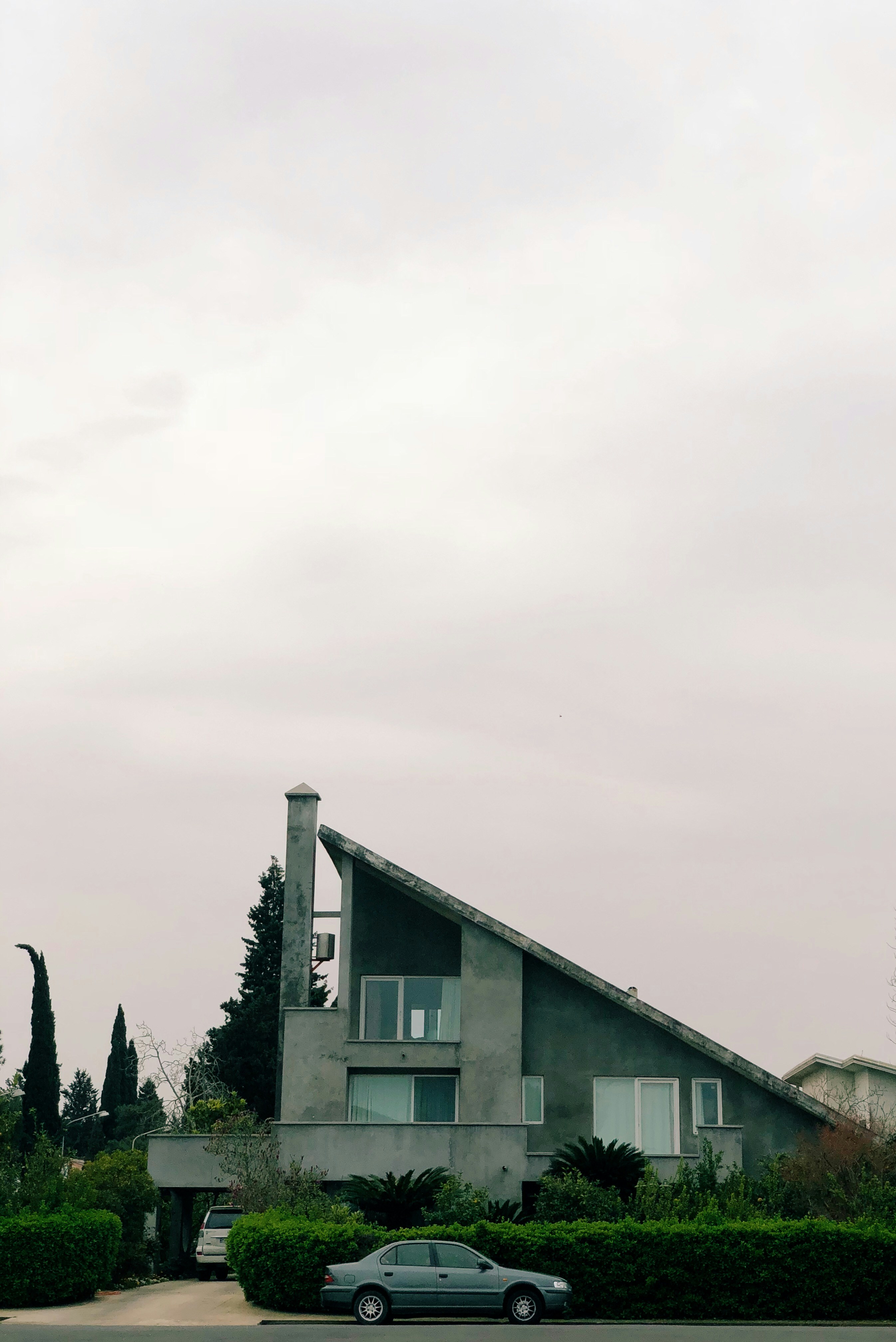 Contemporary angular house with sloped roof against a cloudy sky.