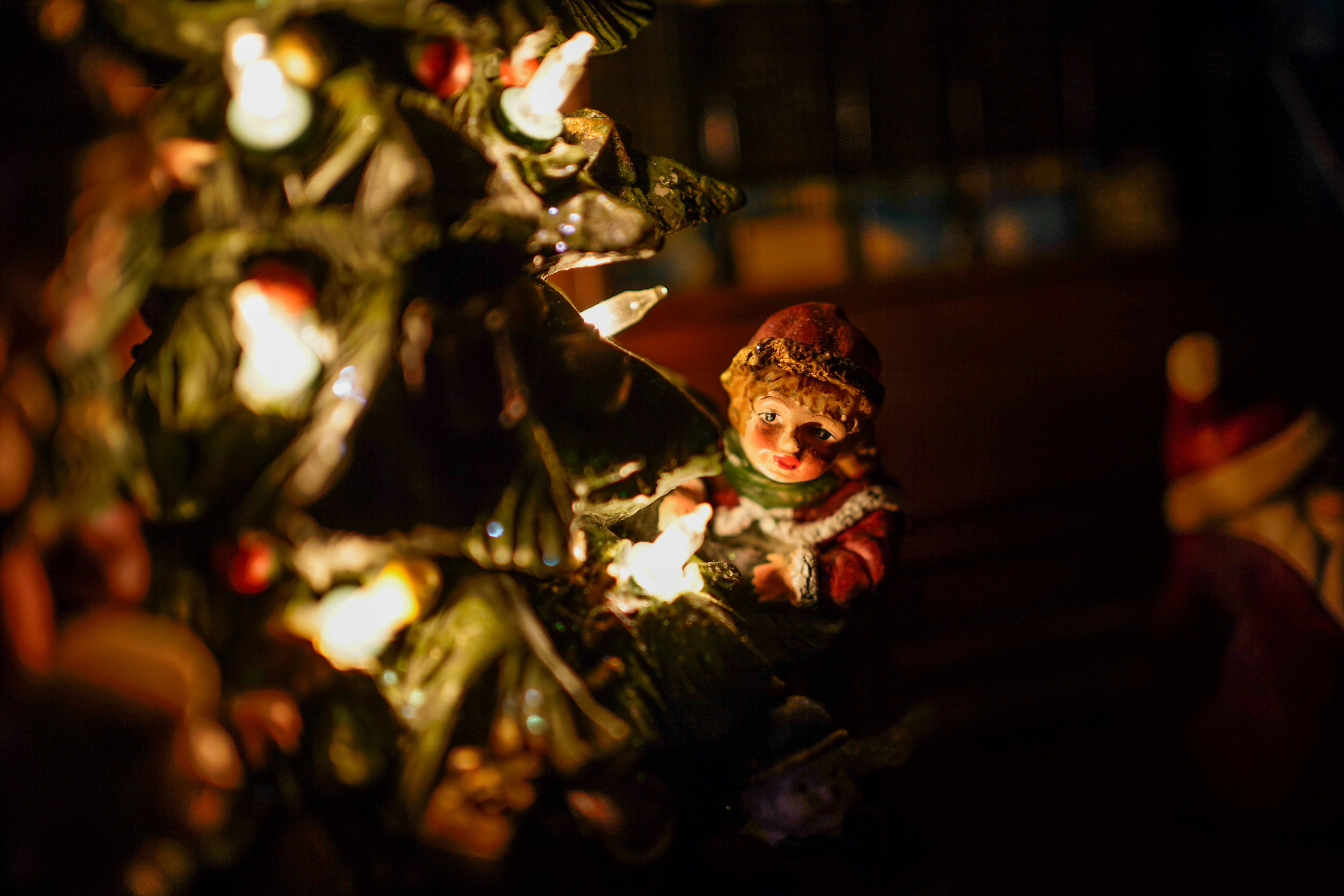 Dim Christmas Glow: A Toy Angel Amid the Tree Ornaments