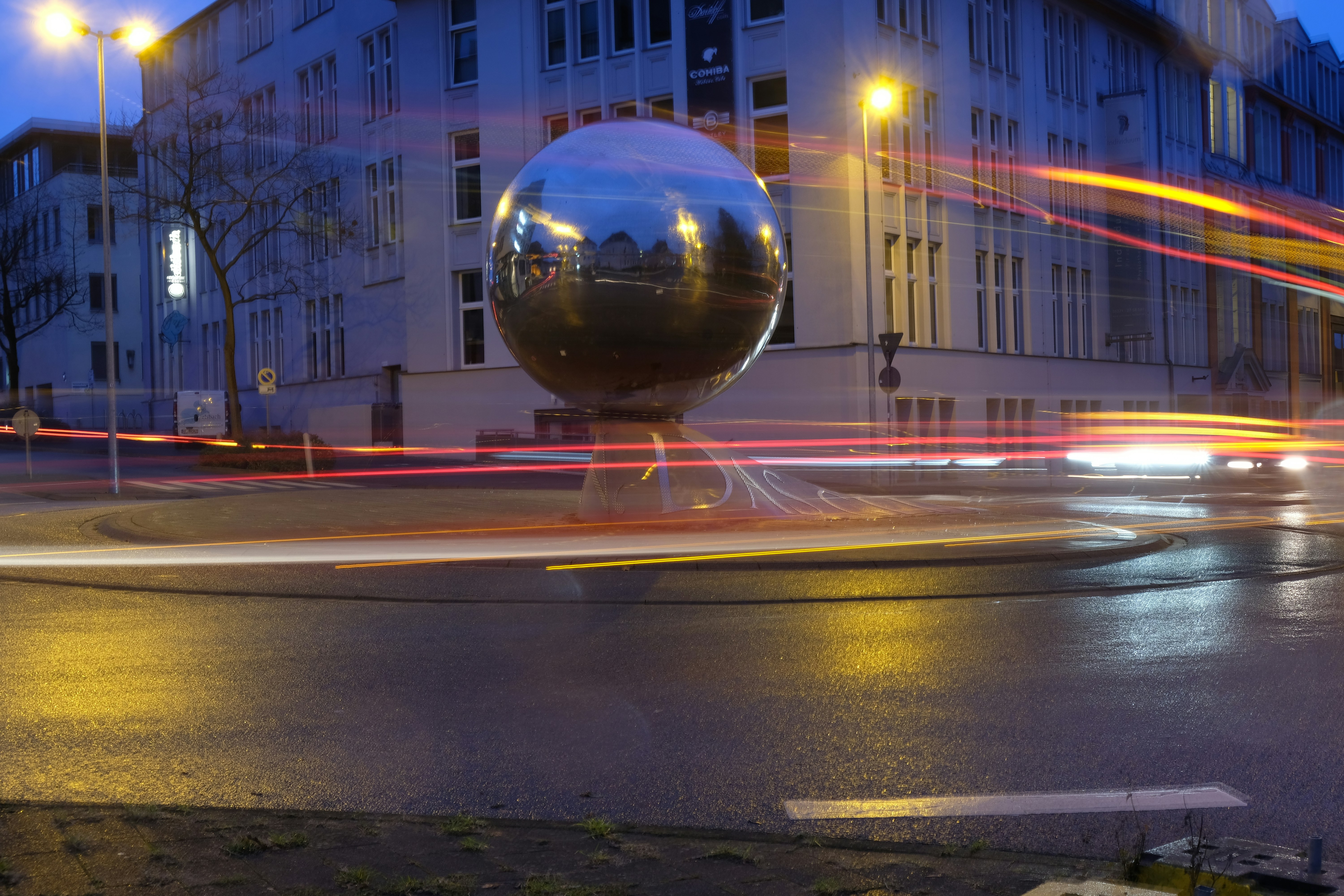 The Neon Orb: Reflective Sphere Amid Moving Light Trails