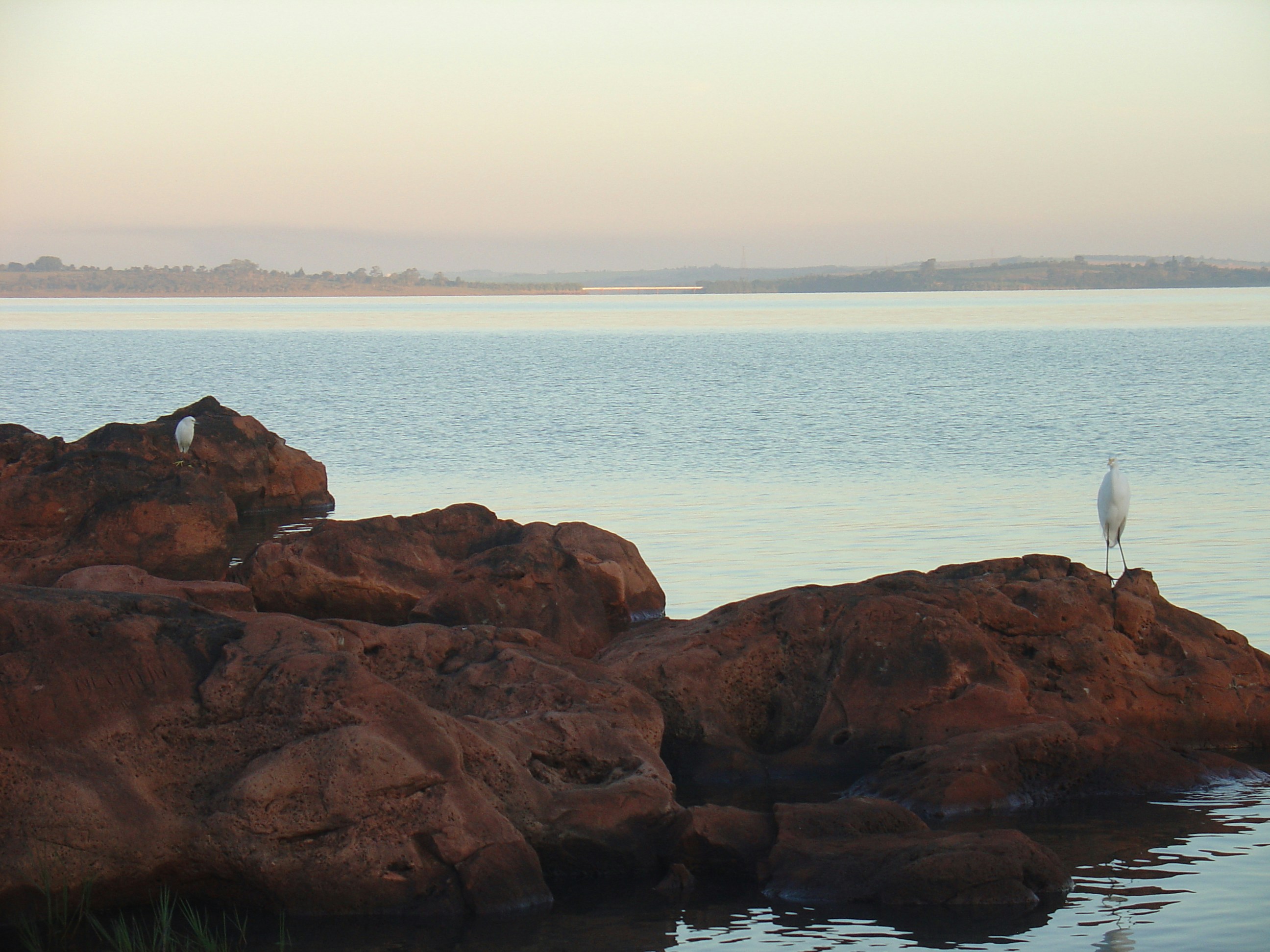 Serene river landscape with rocky foreground at dusk.