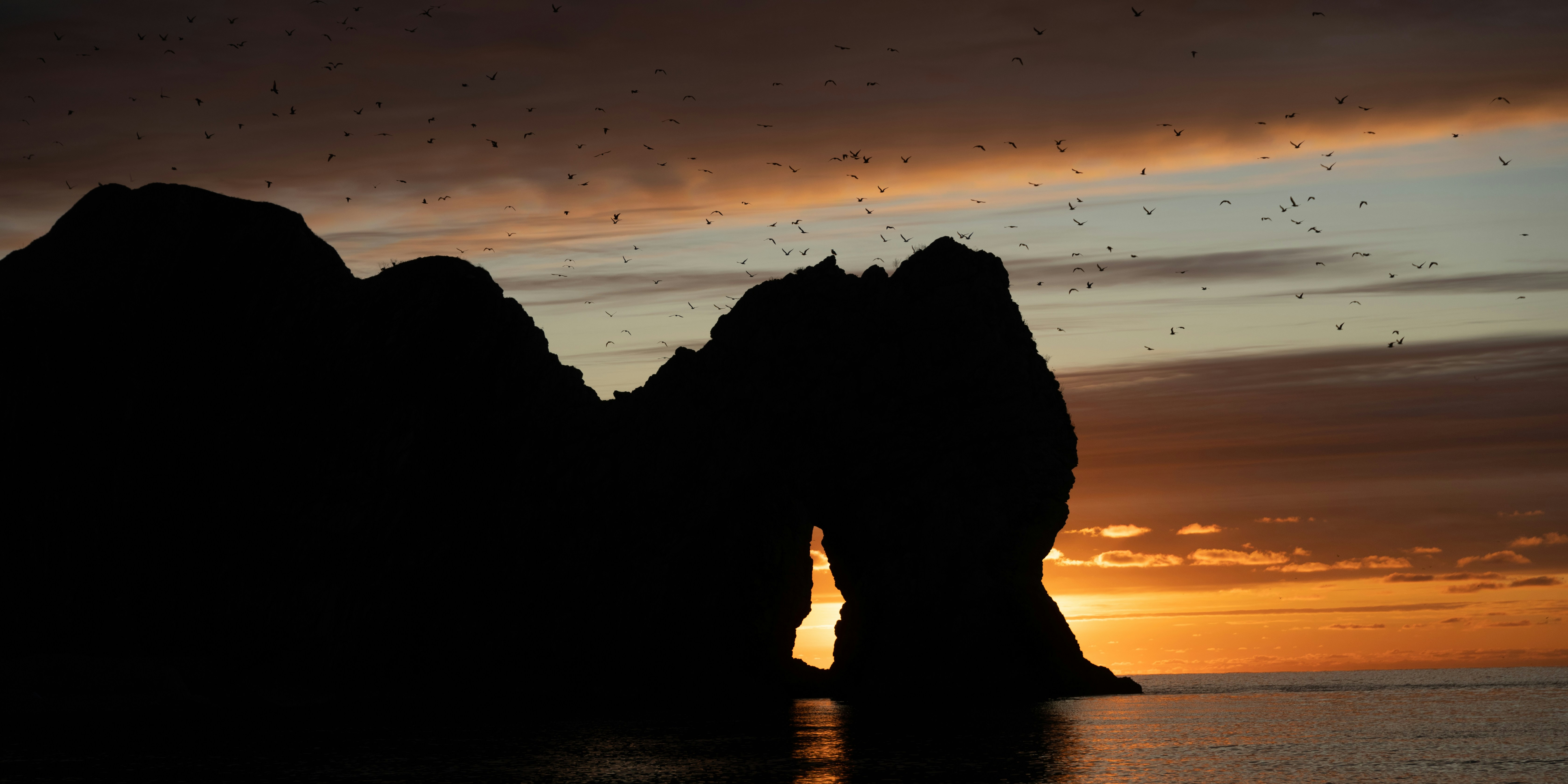 Silhouette Arch at Sunset: A Coastal Gateway Framed by Dusk