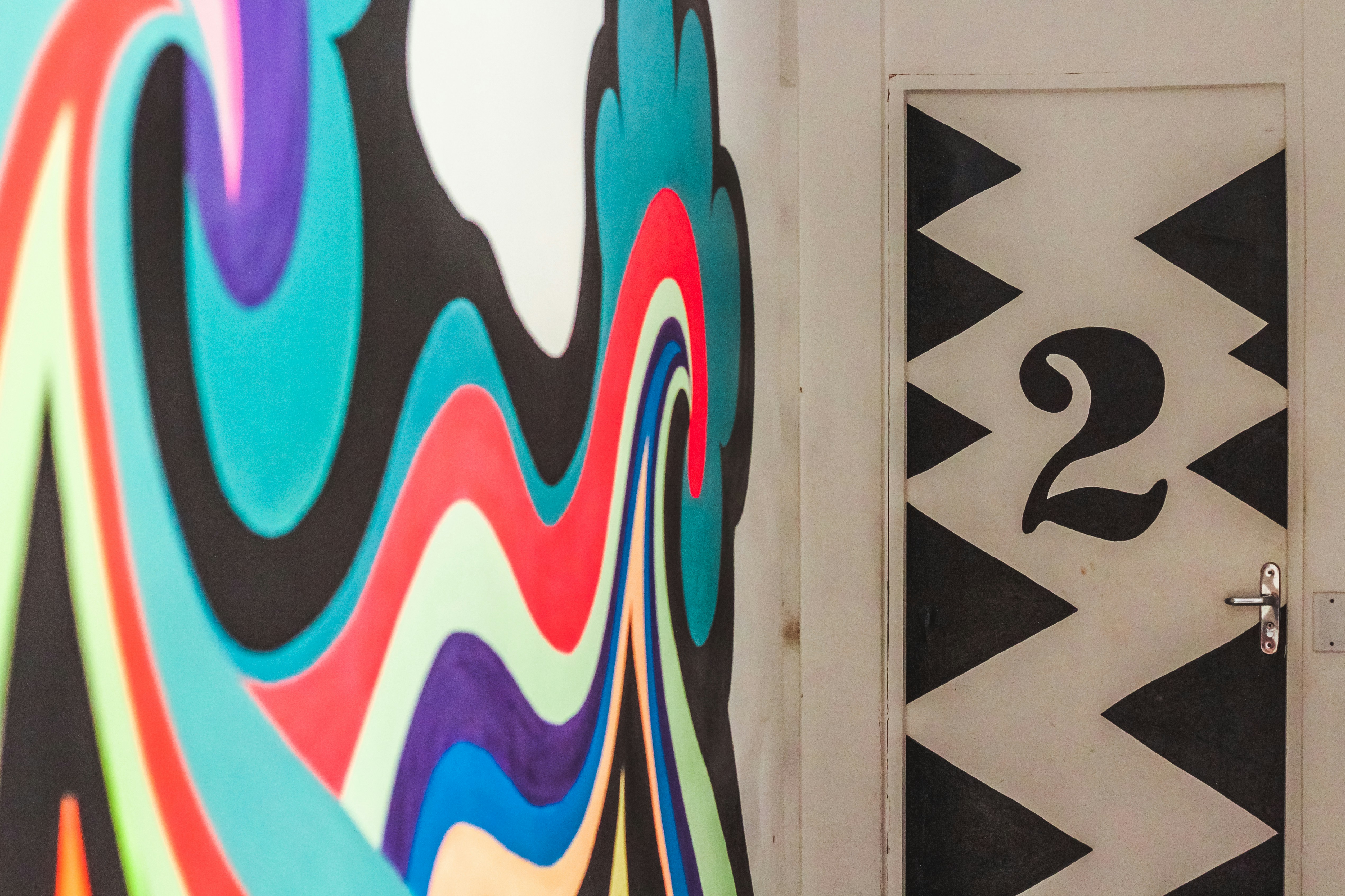Colorful abstract mural next to a door with bold geometric patterns and the number two.