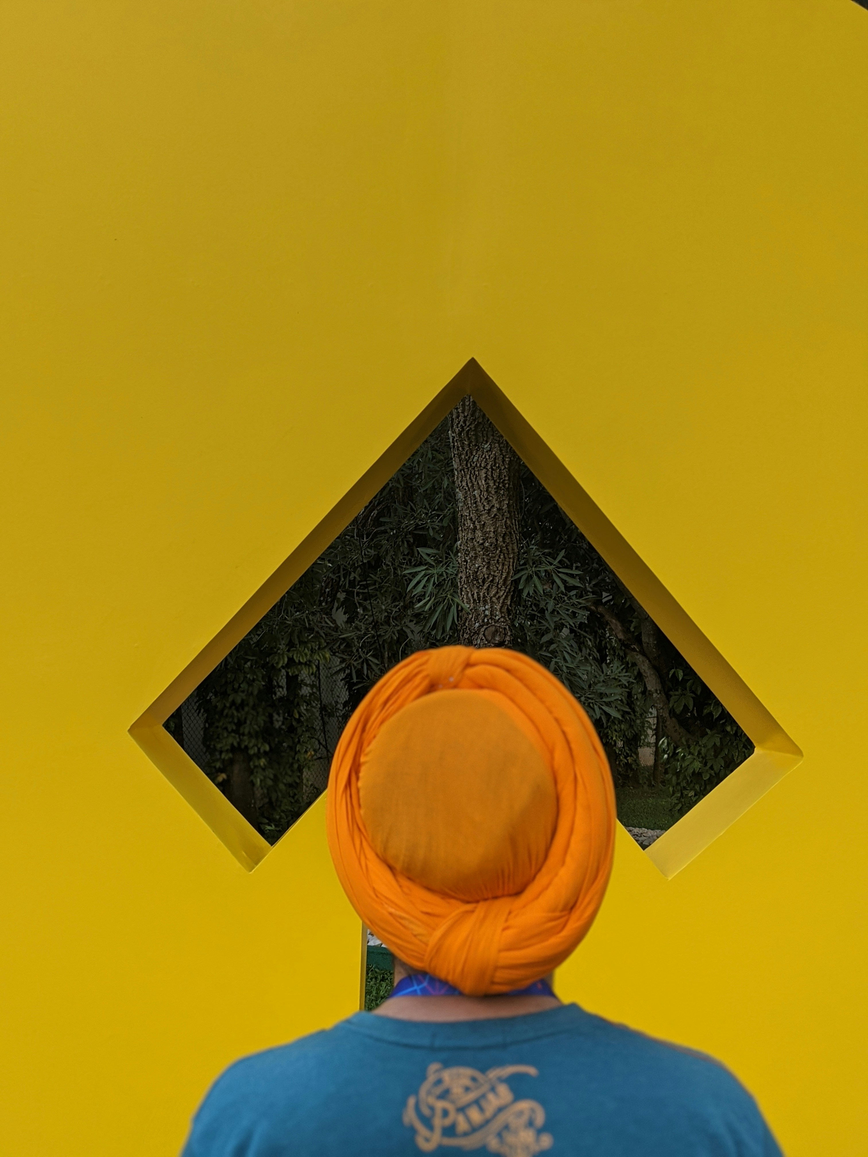 Turbaned Figure Framed by a Diamond Window in a Sunlit Yellow Wall