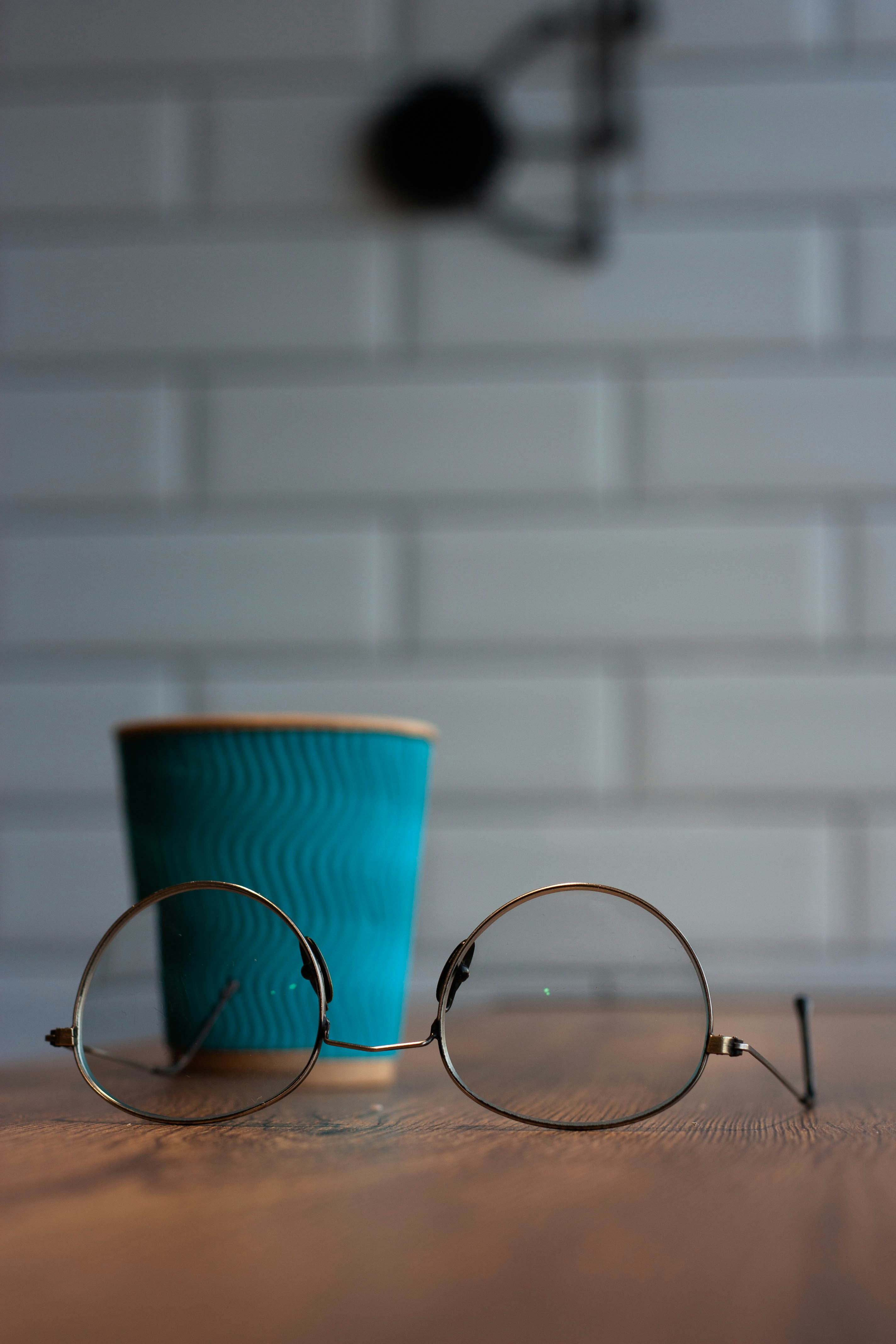 Curves on Wood: Round Glasses Framed by a Teal Cup in Soft Focus