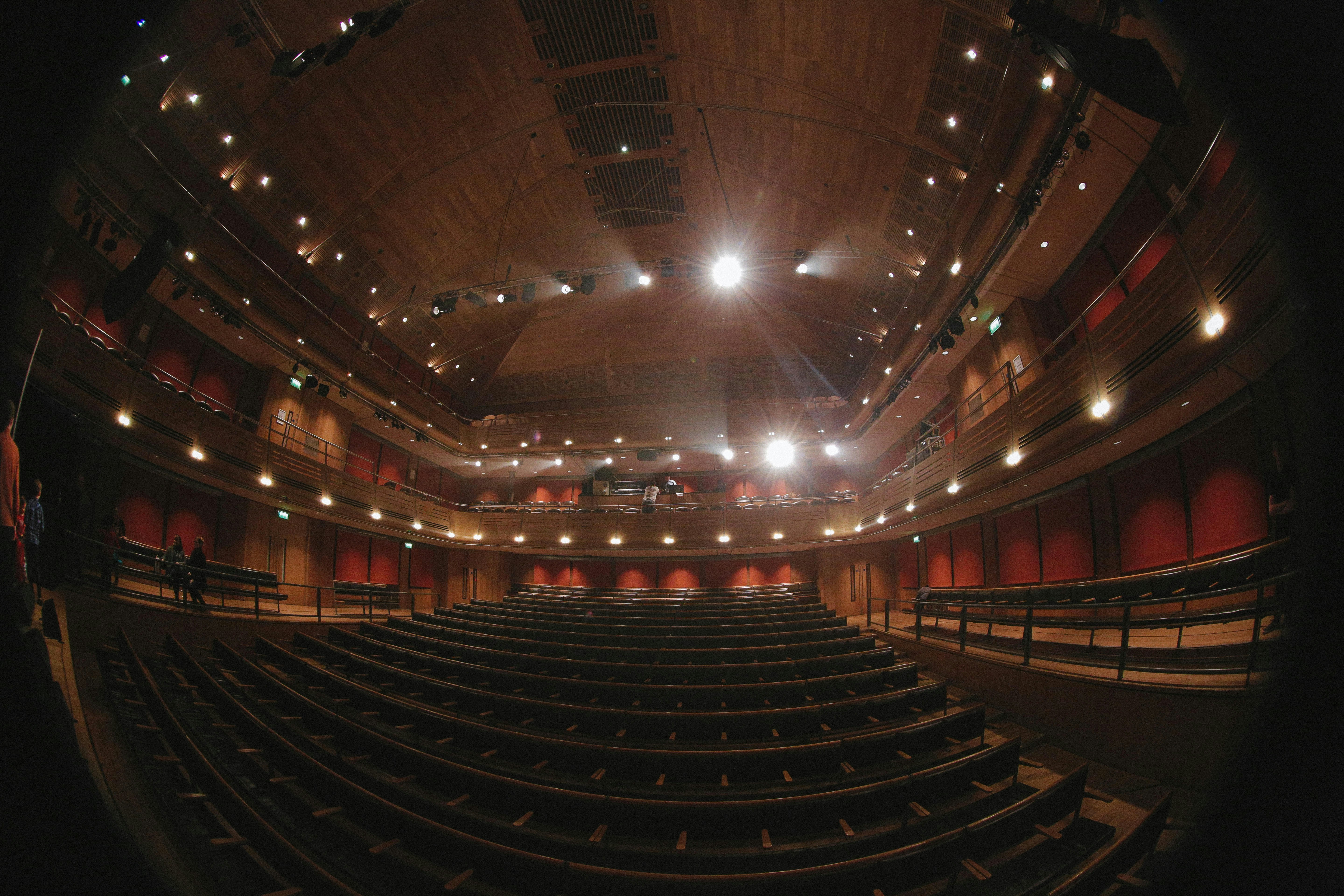 Wide-angle view of an auditorium with tiered seating and illuminated stage lights.