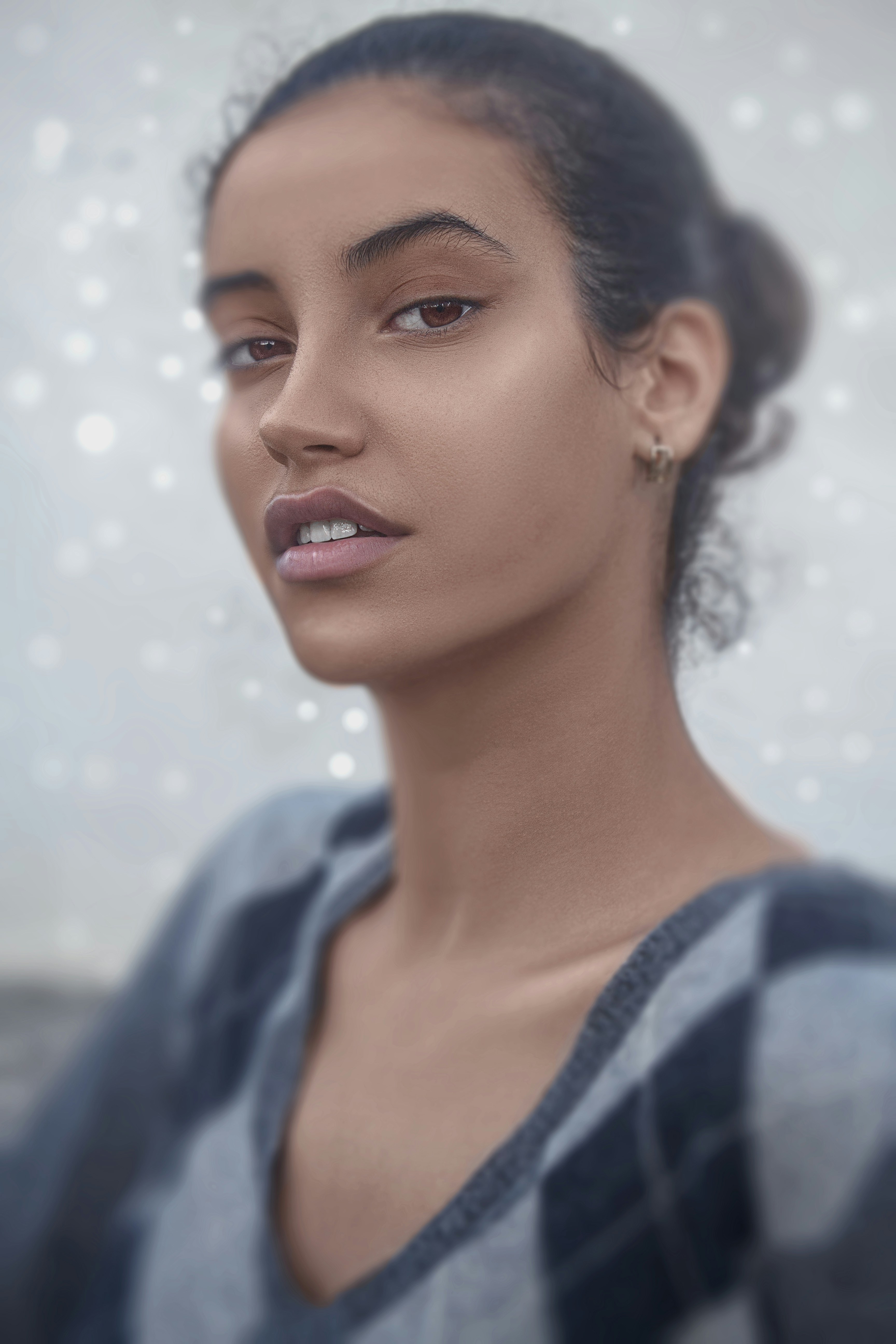 A portrait of a young woman with a subtle expression, dressed in a checkered sweater, set against a softly blurred background. The focus is on her serene demeanor.