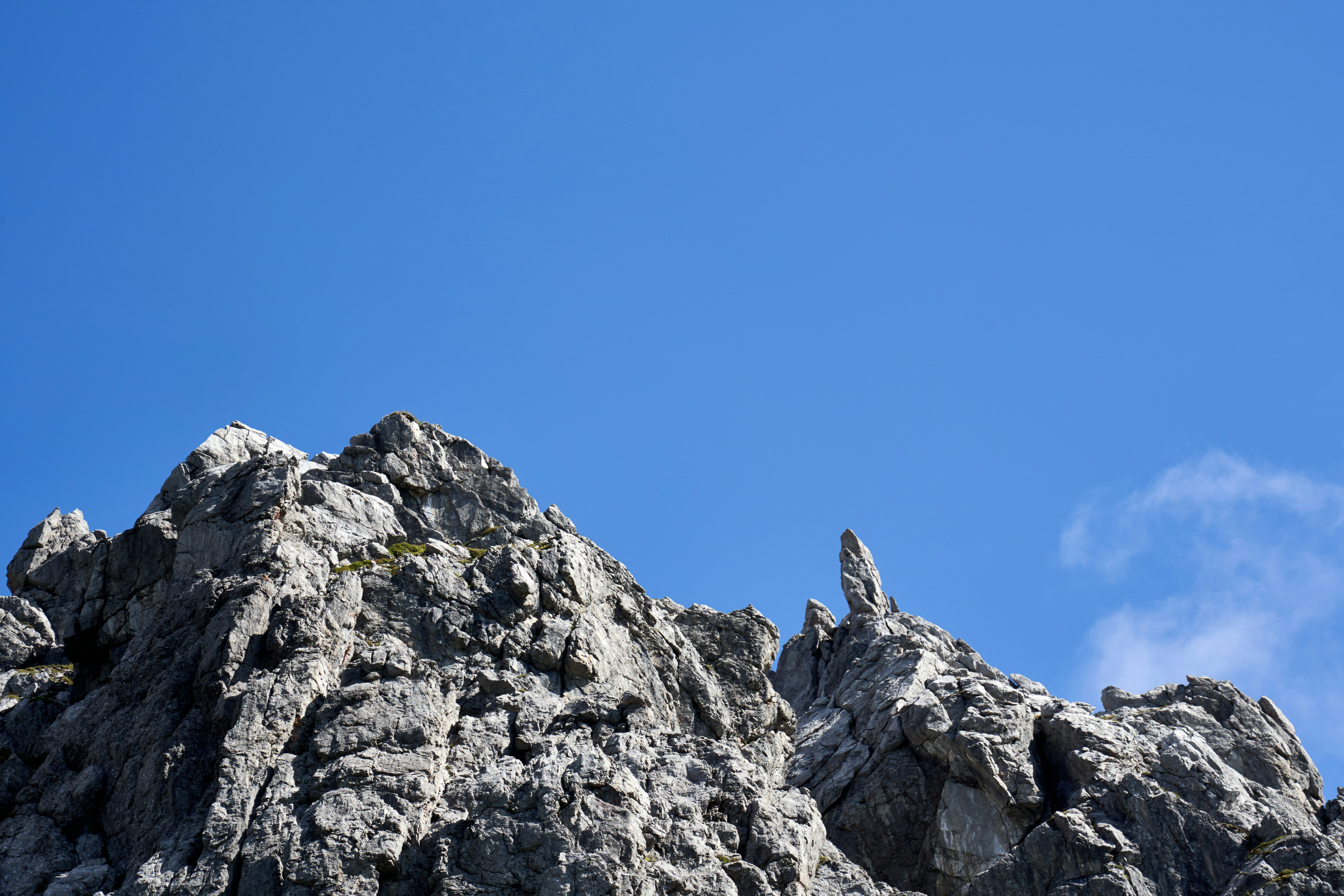 Jagged rock formations rise against a clear blue sky, showcasing the rugged beauty of nature's architecture.