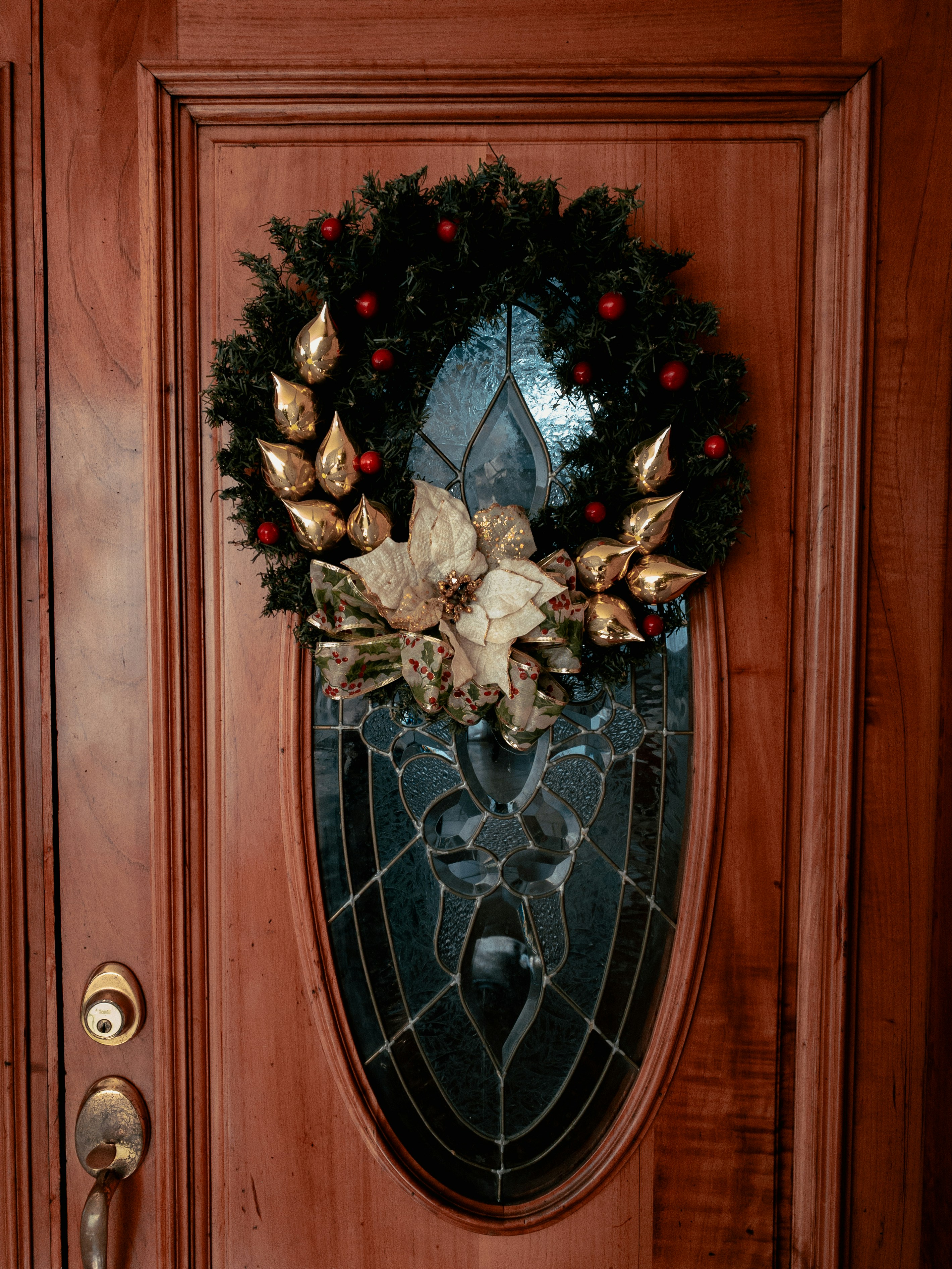 Holiday Wreath Framed by a Carved Wooden Door and Jewel-Toned Glass
