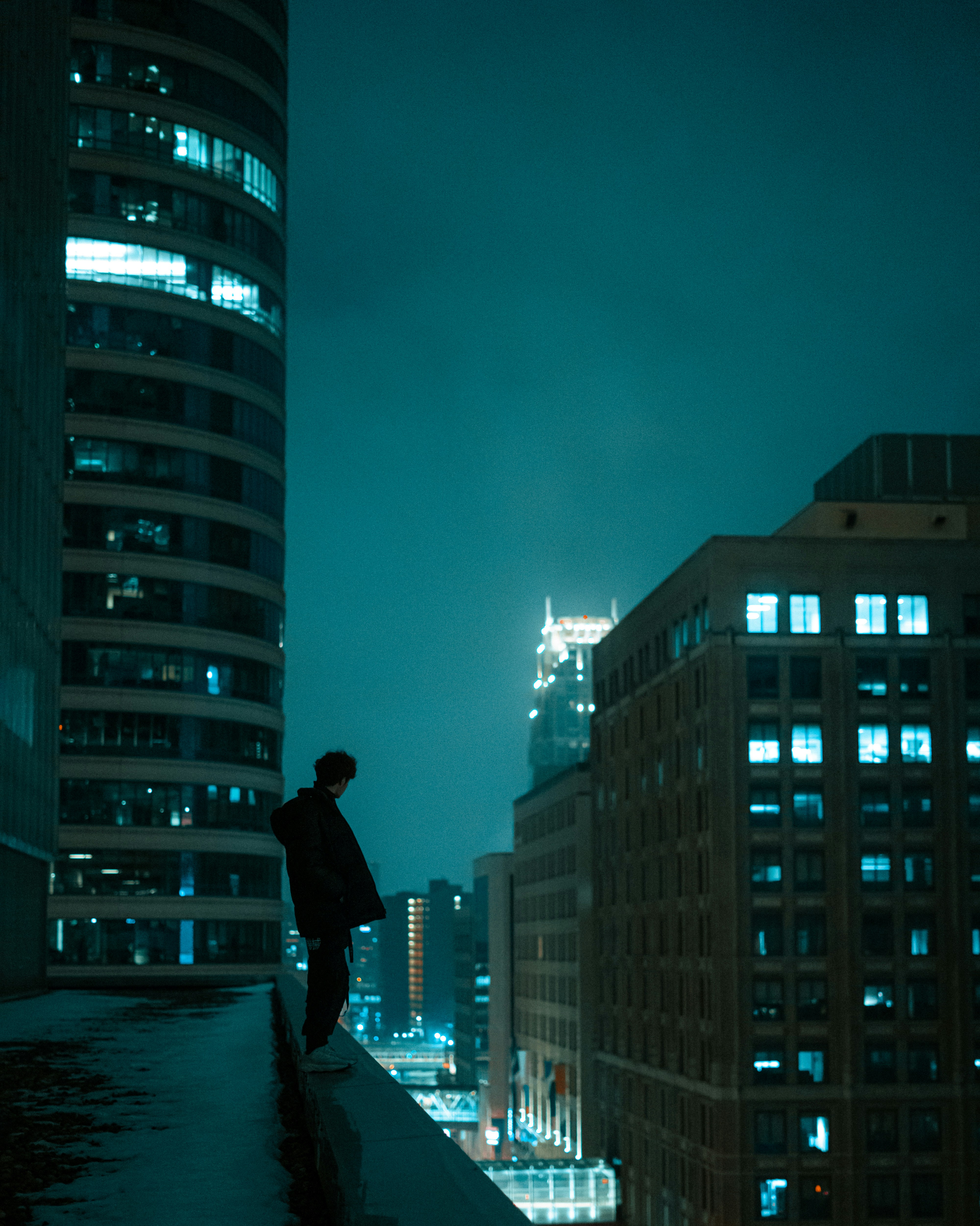 Man standing on rooftop viewing city with high-rise buildings during ...
