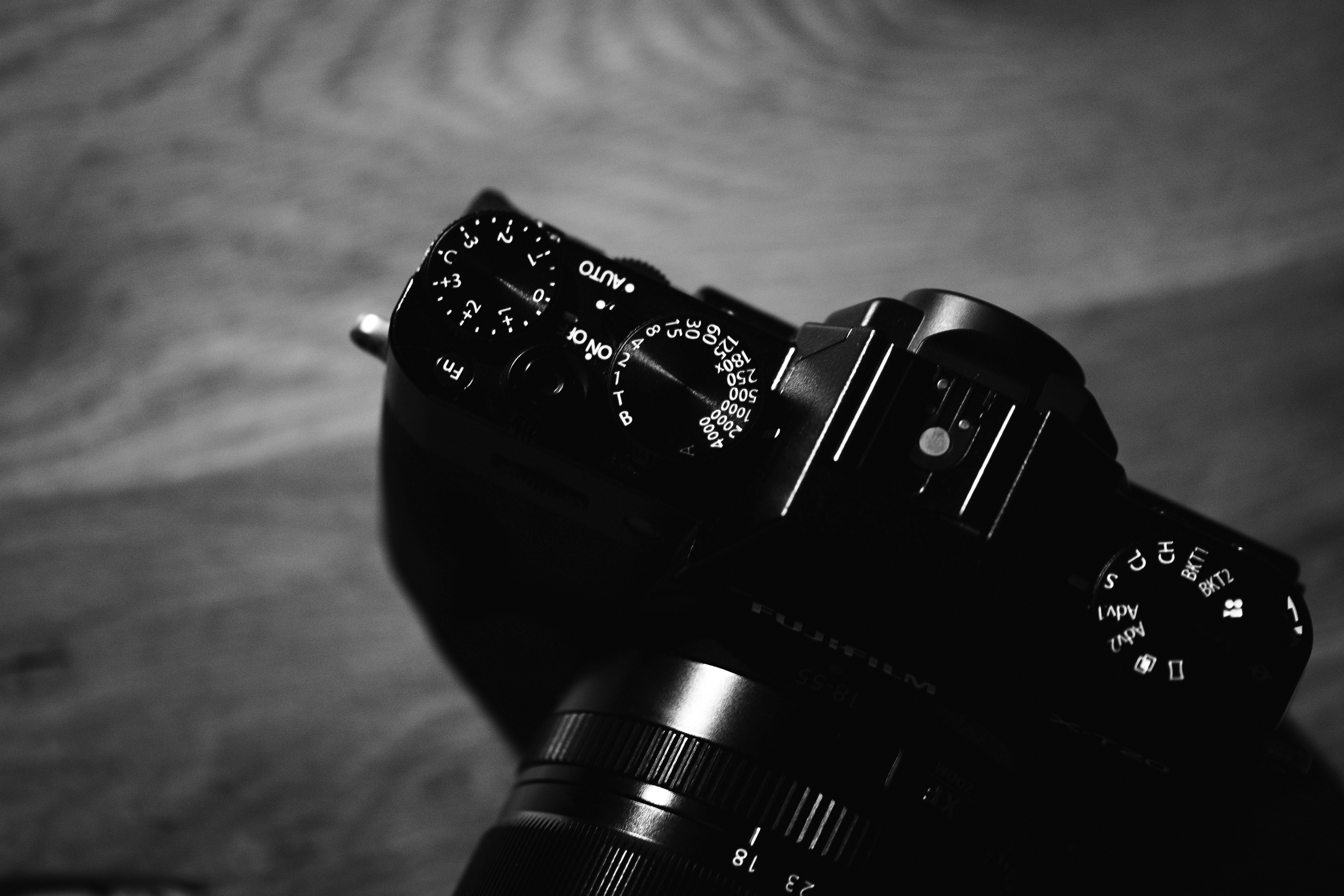 Black and white close-up of a Fujifilm X-T20 camera with focus on dials and controls.