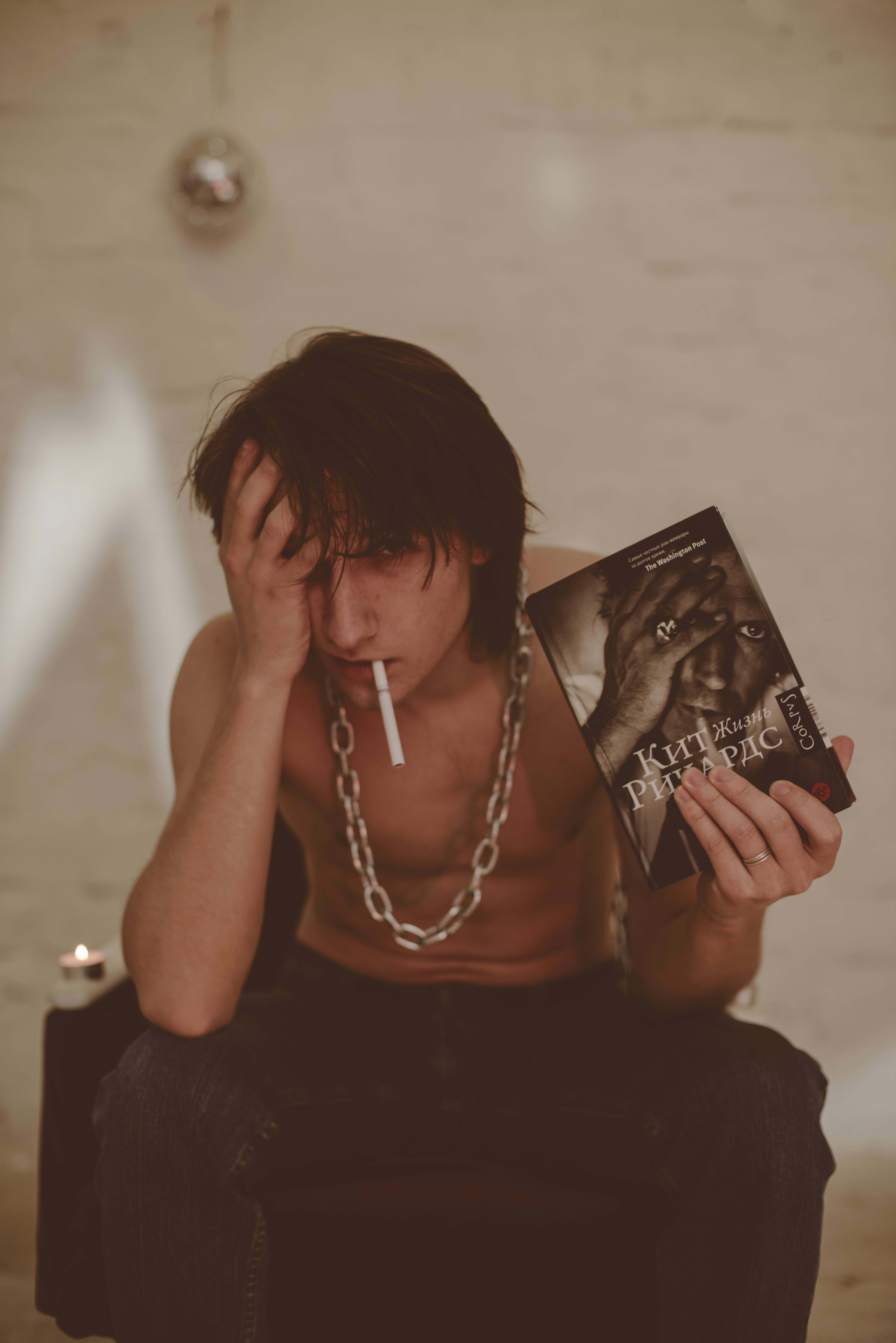 Candlelit Contemplation: A Chain-Wearing Rebel Pauses with a Cigarette and a Paperback