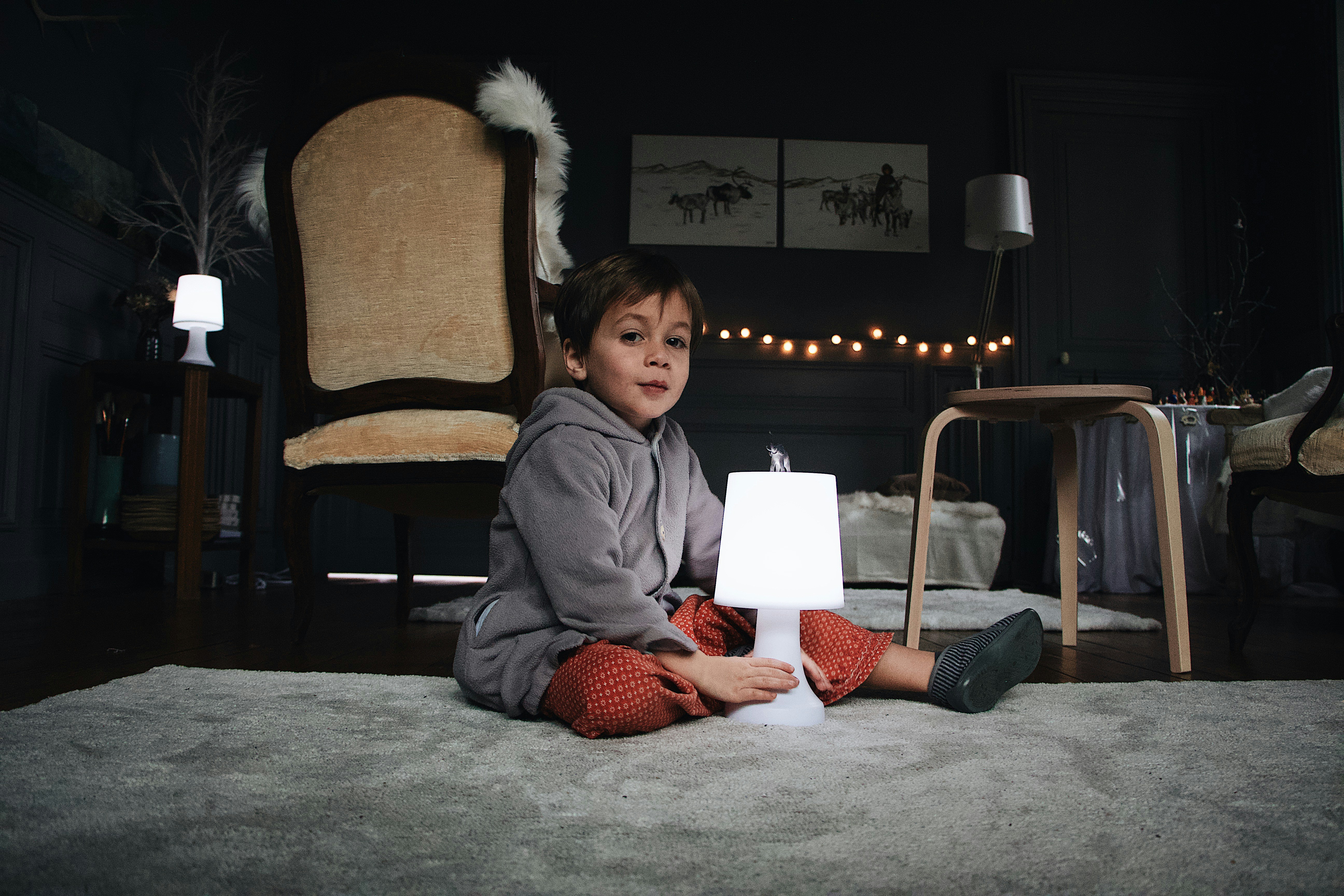 Warm Glow, Quiet Play: A Child with a Lamp in a Dim Living Room