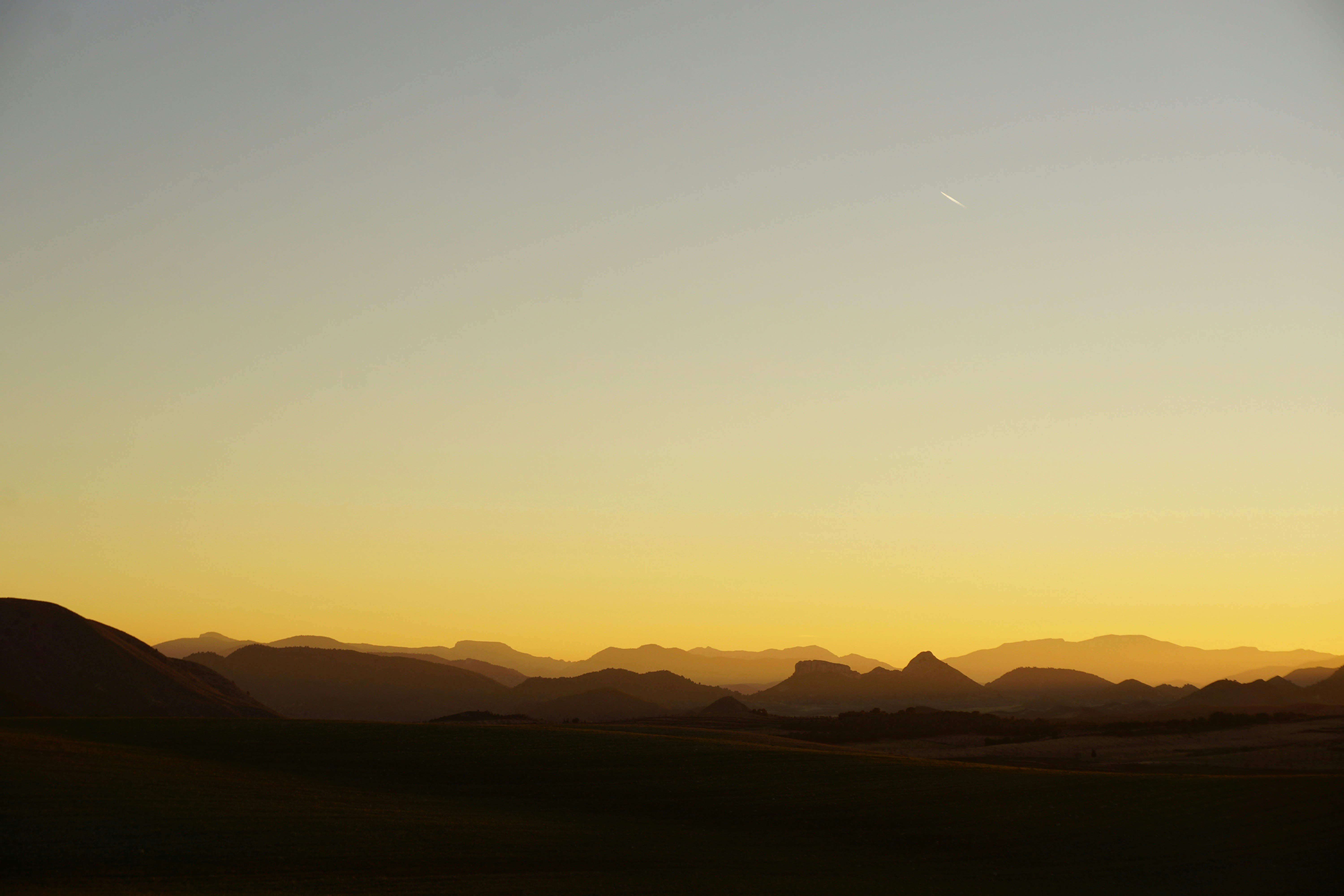 Silhouetted mountain range under a golden dusk sky.