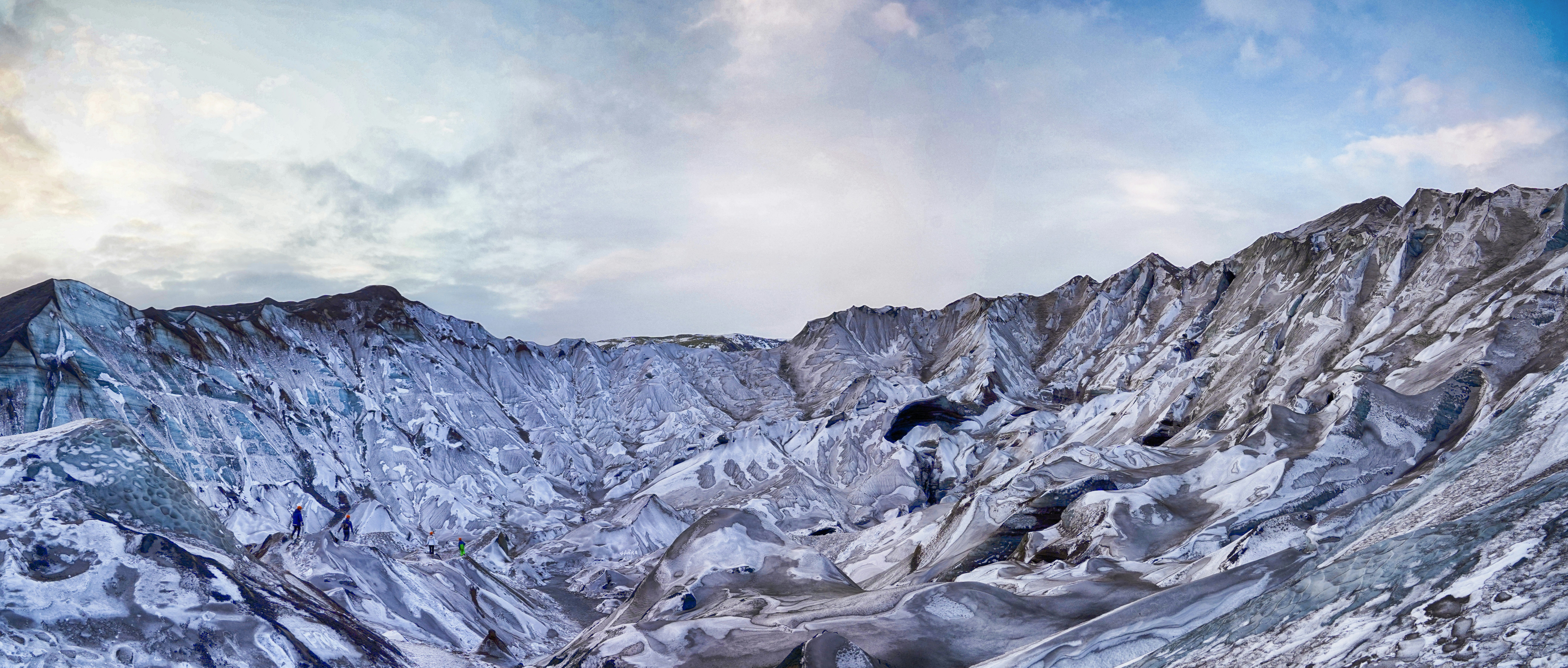 Expansive glacier landscape showcasing intricate ice formations and rugged terrain under a soft blue sky.