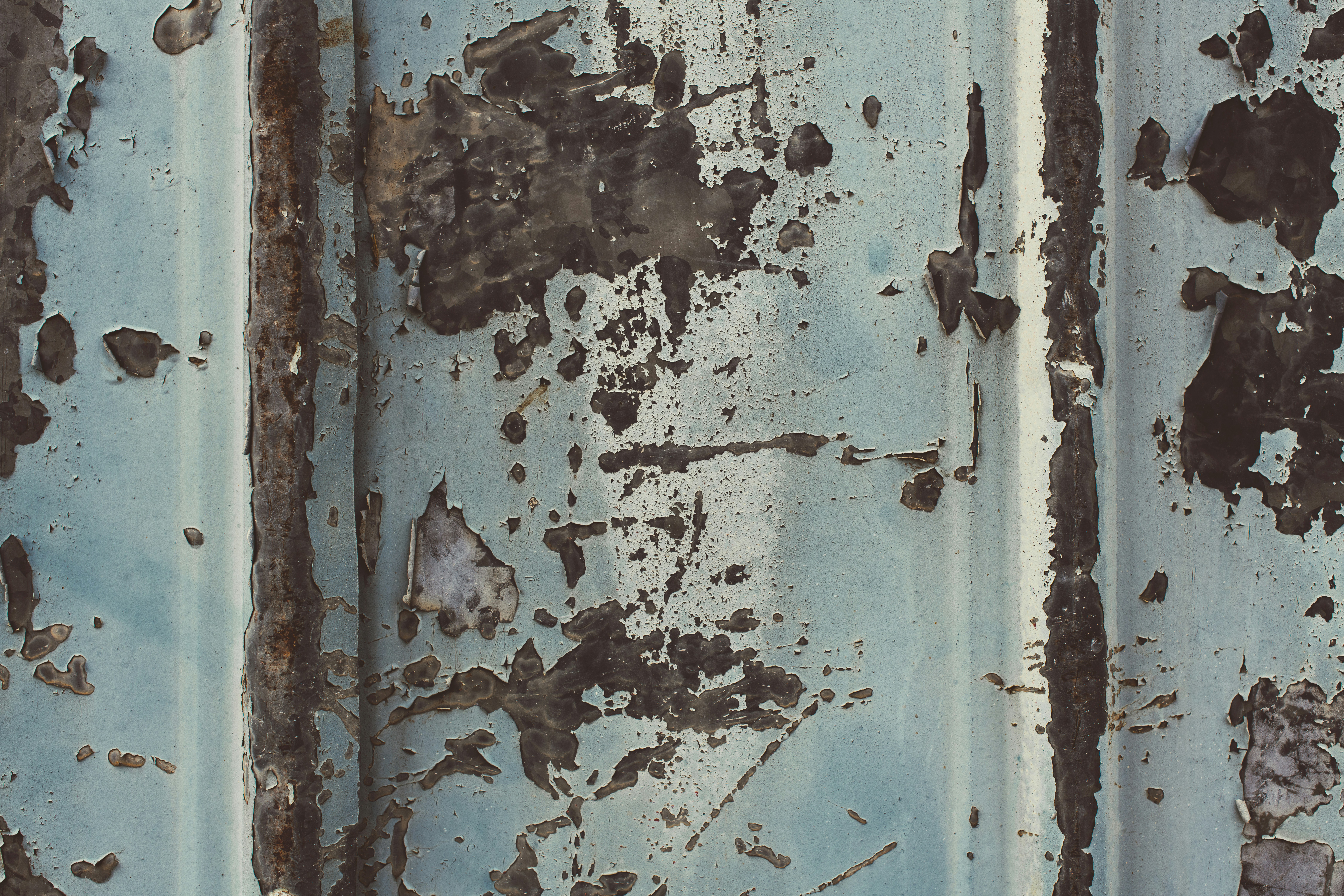 Weathered metal surface showcasing layers of peeling paint and rust, revealing a rich texture and history.
