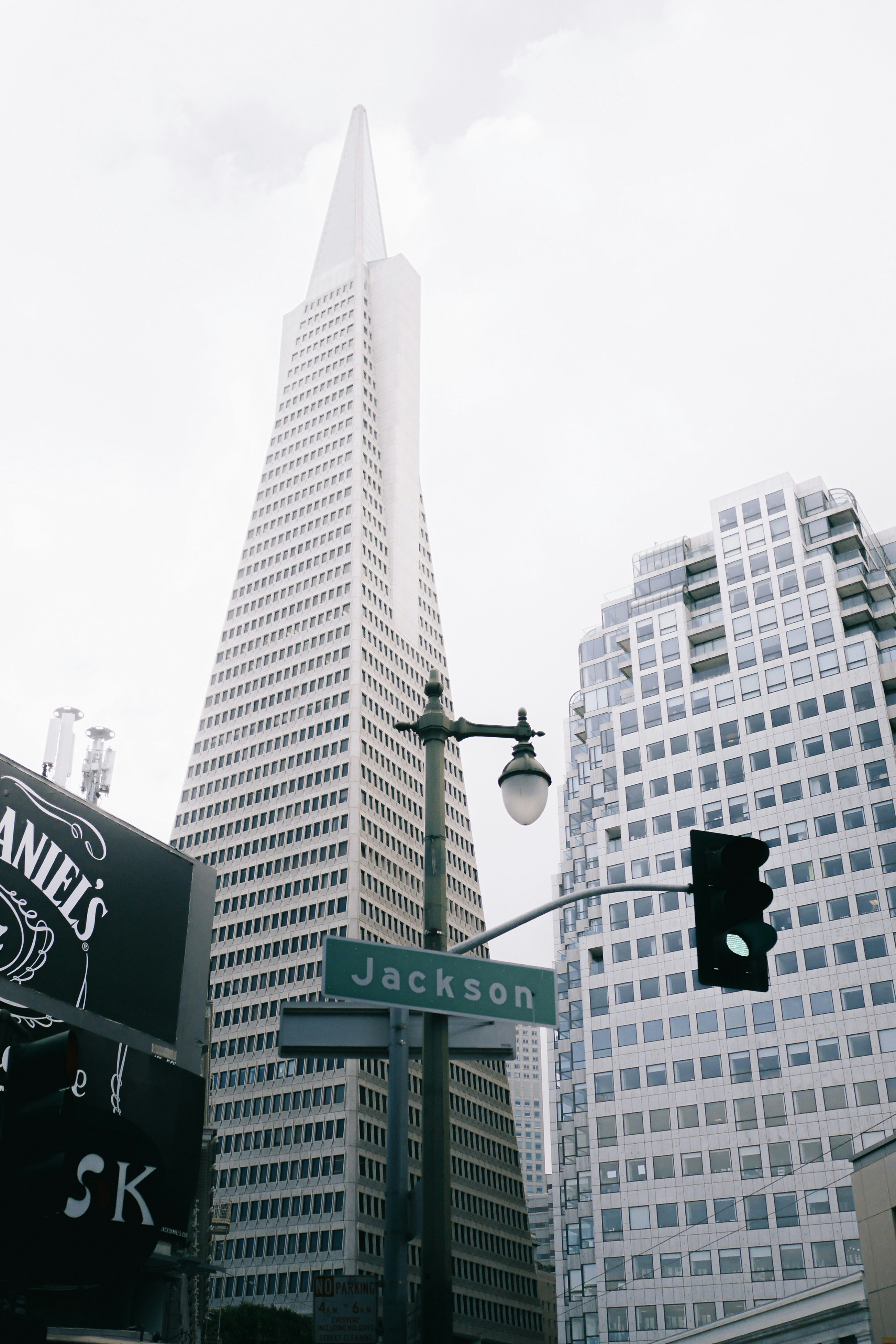 Photograph capturing a San Francisco street scene with the Transamerica Pyramid rising above Jackson Street and glassy office buildings.