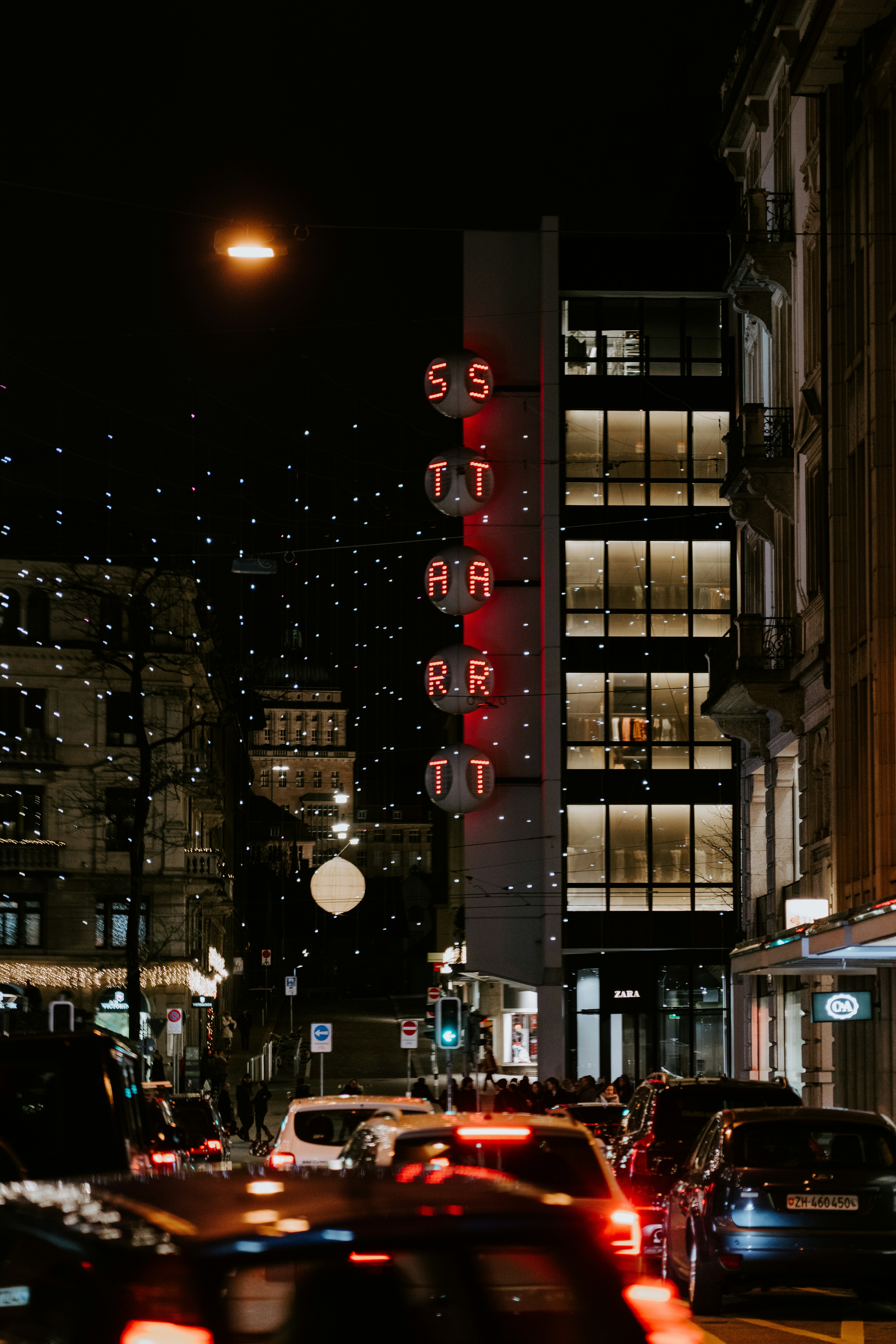 People walking on pathway near buildings and different vehicles on road ...