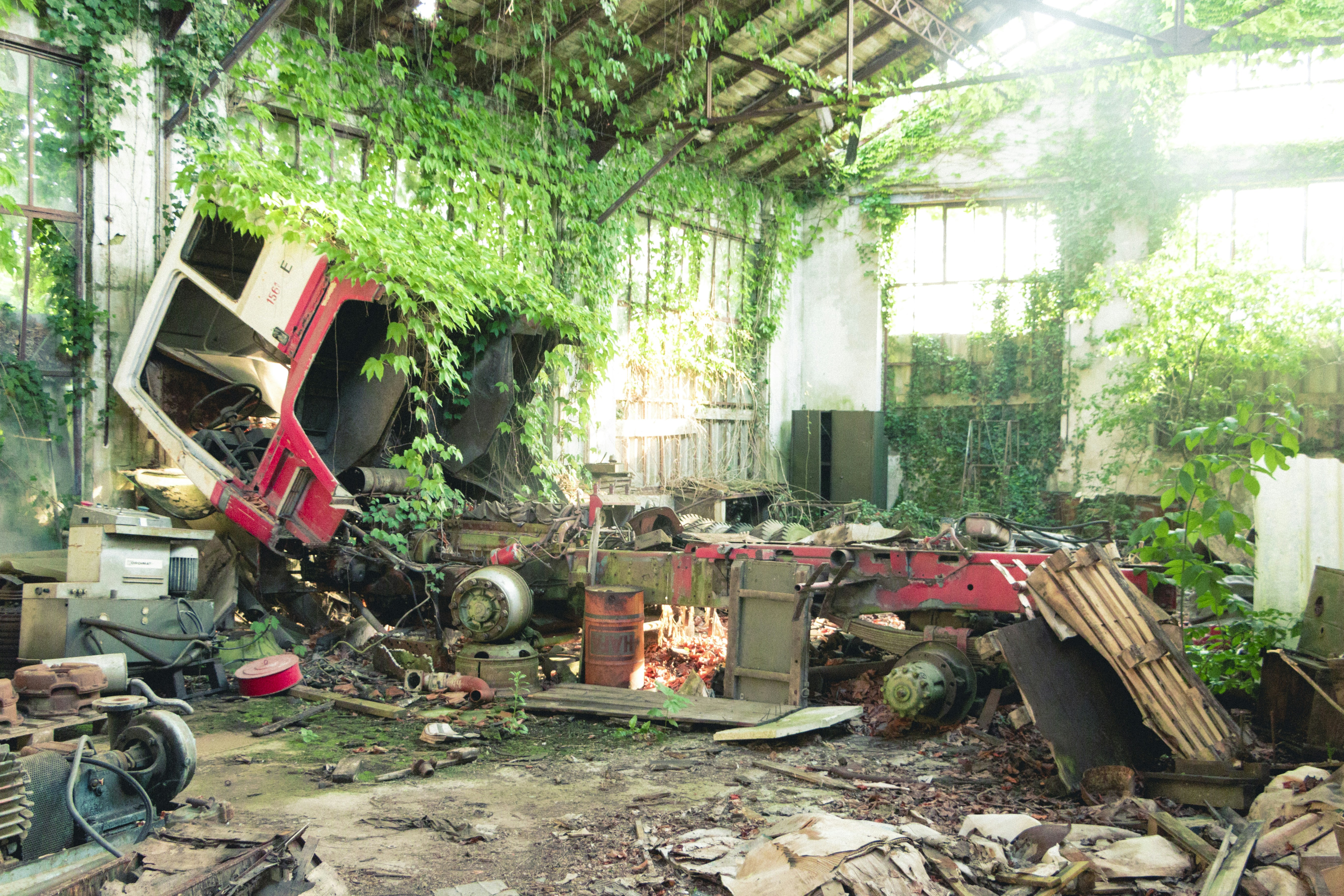 Tilted Red Truck Amid Green Overgrowth in a Forgotten Depot