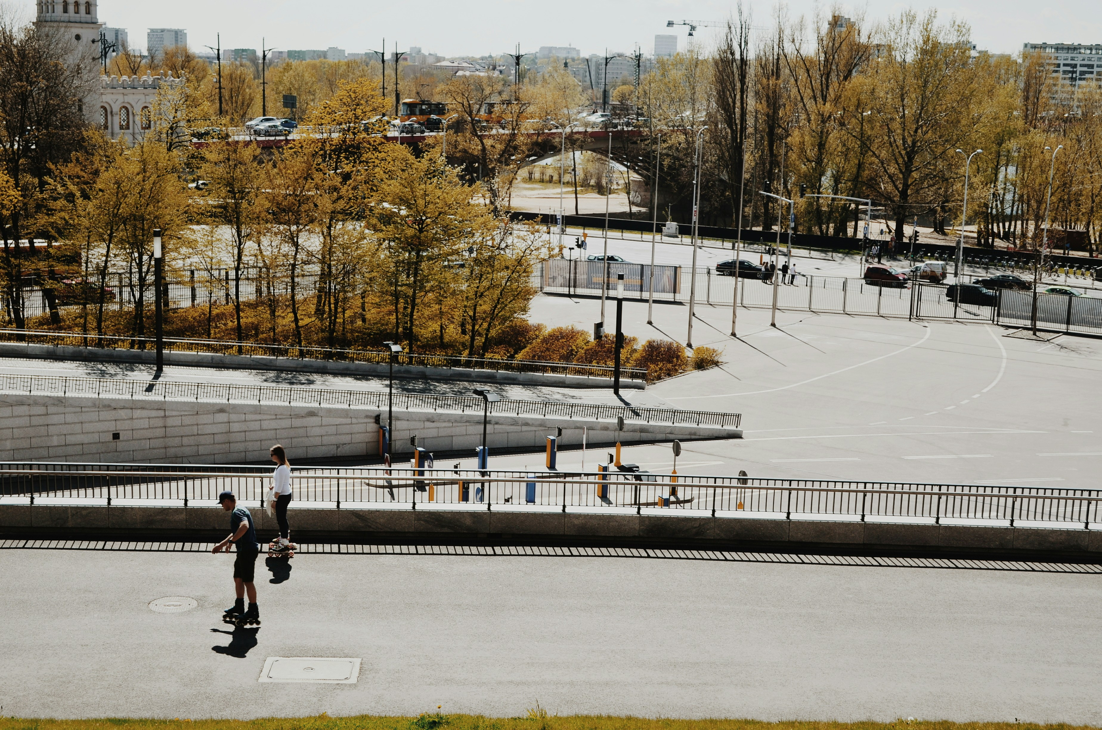 Two Pedestrians in Autumn Light Crossing a Quiet City Plaza