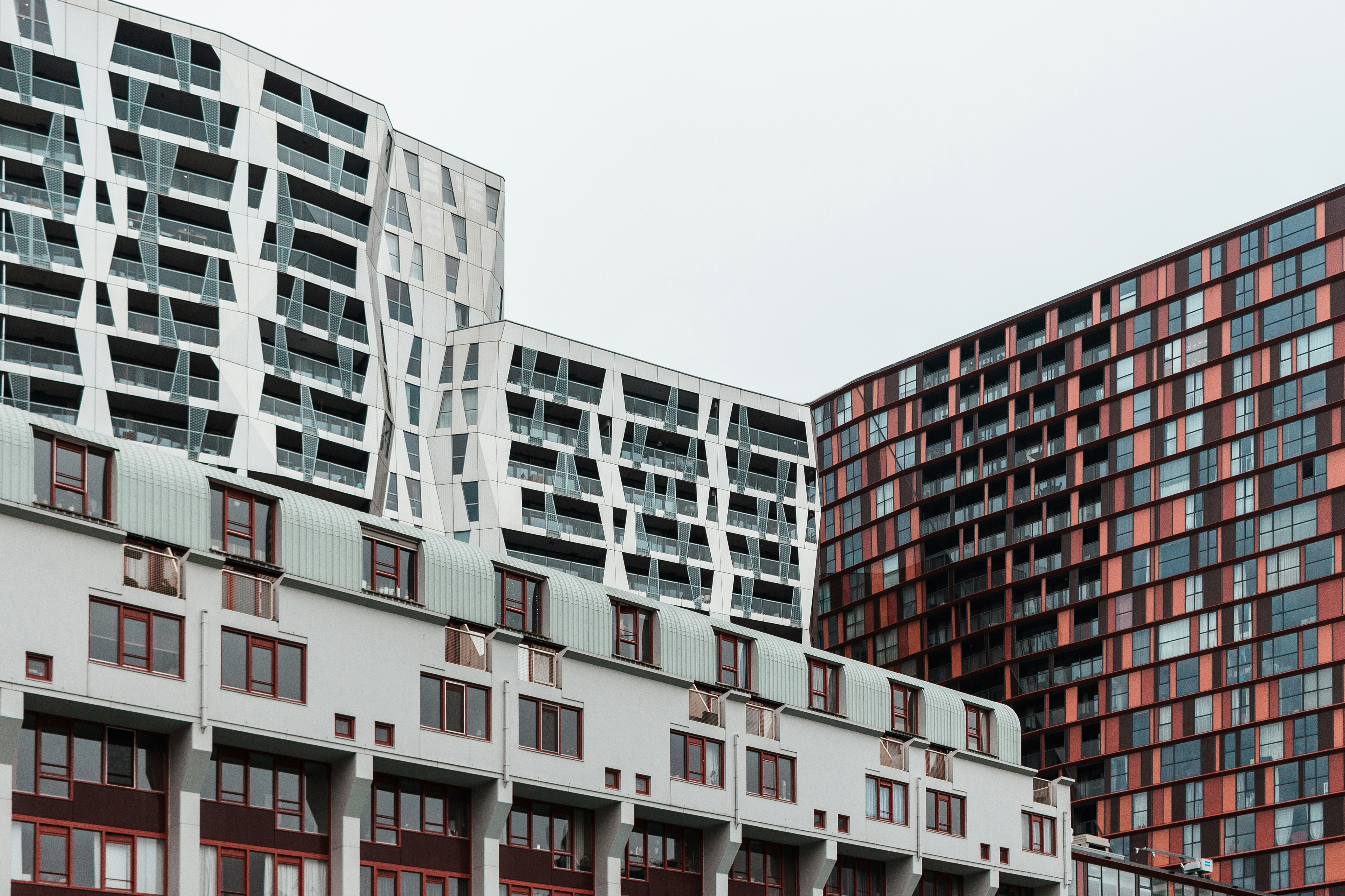 A juxtaposition of contemporary apartment buildings showcasing unique architectural designs and color palettes. The structures create a dynamic urban landscape.