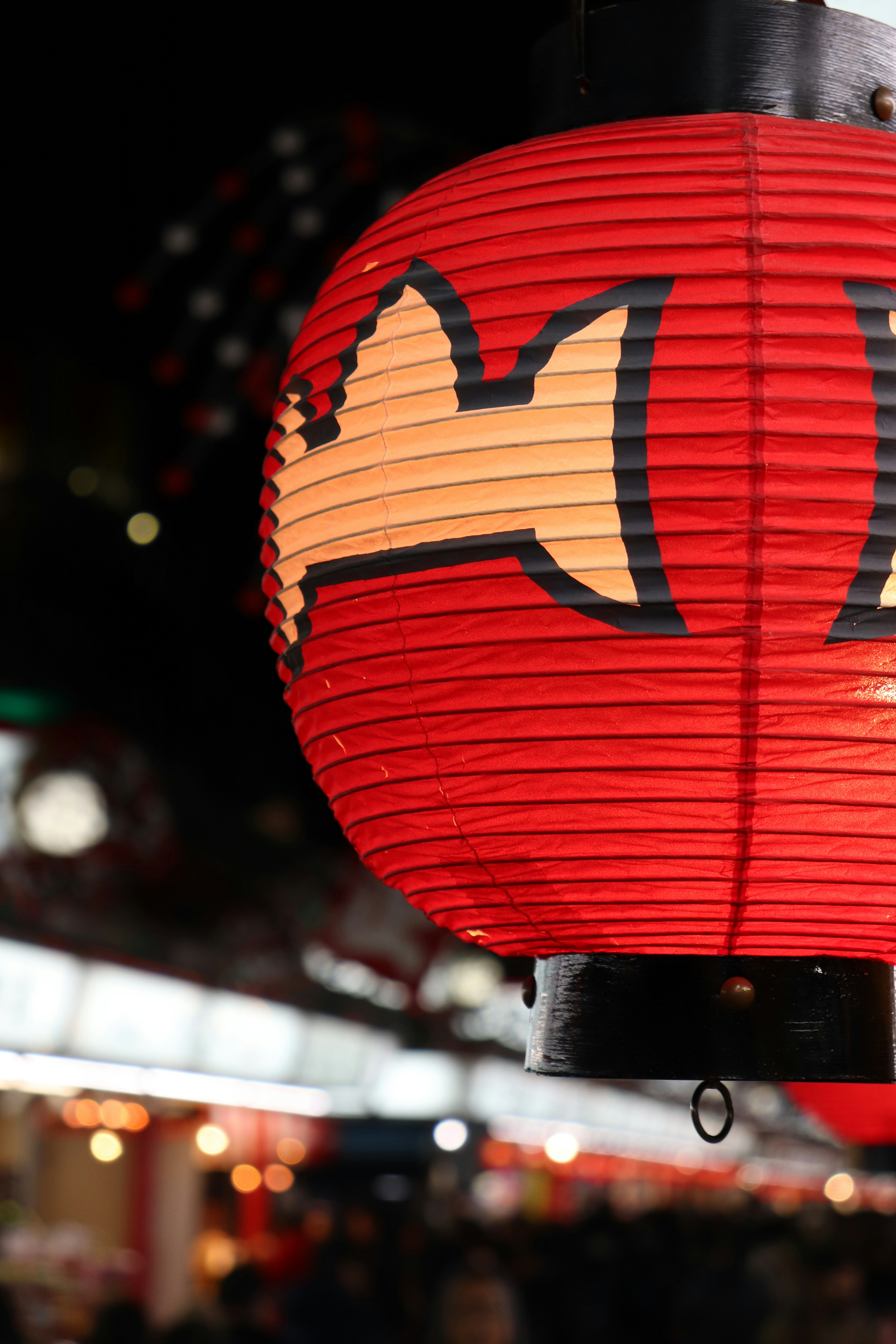 Red Lantern in Focus: A Close Lantern Portrait Amid Night Market Haze