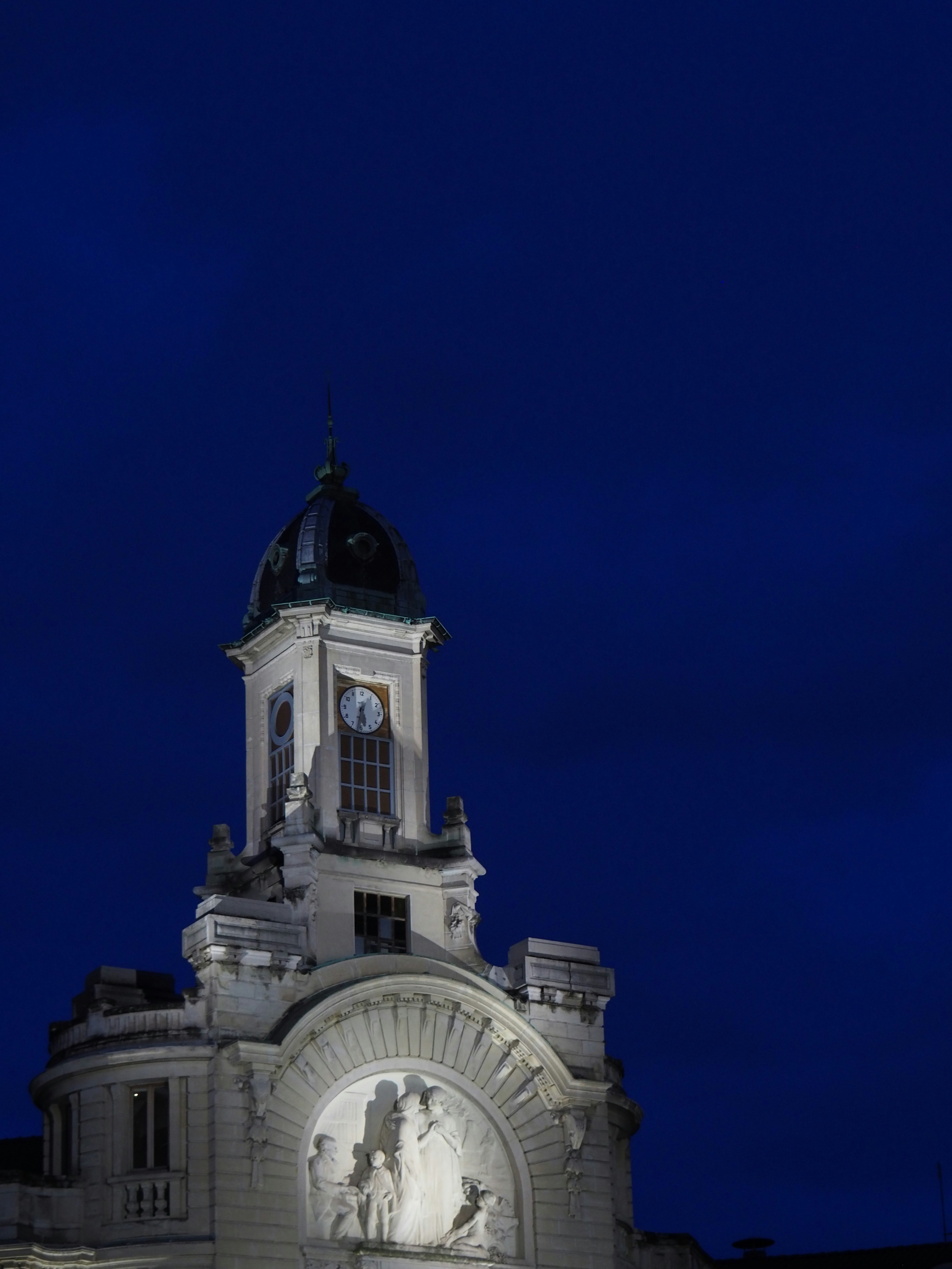 Moonlit Arch: Sculpted Figures Beneath a Beaux-Arts Clock Tower