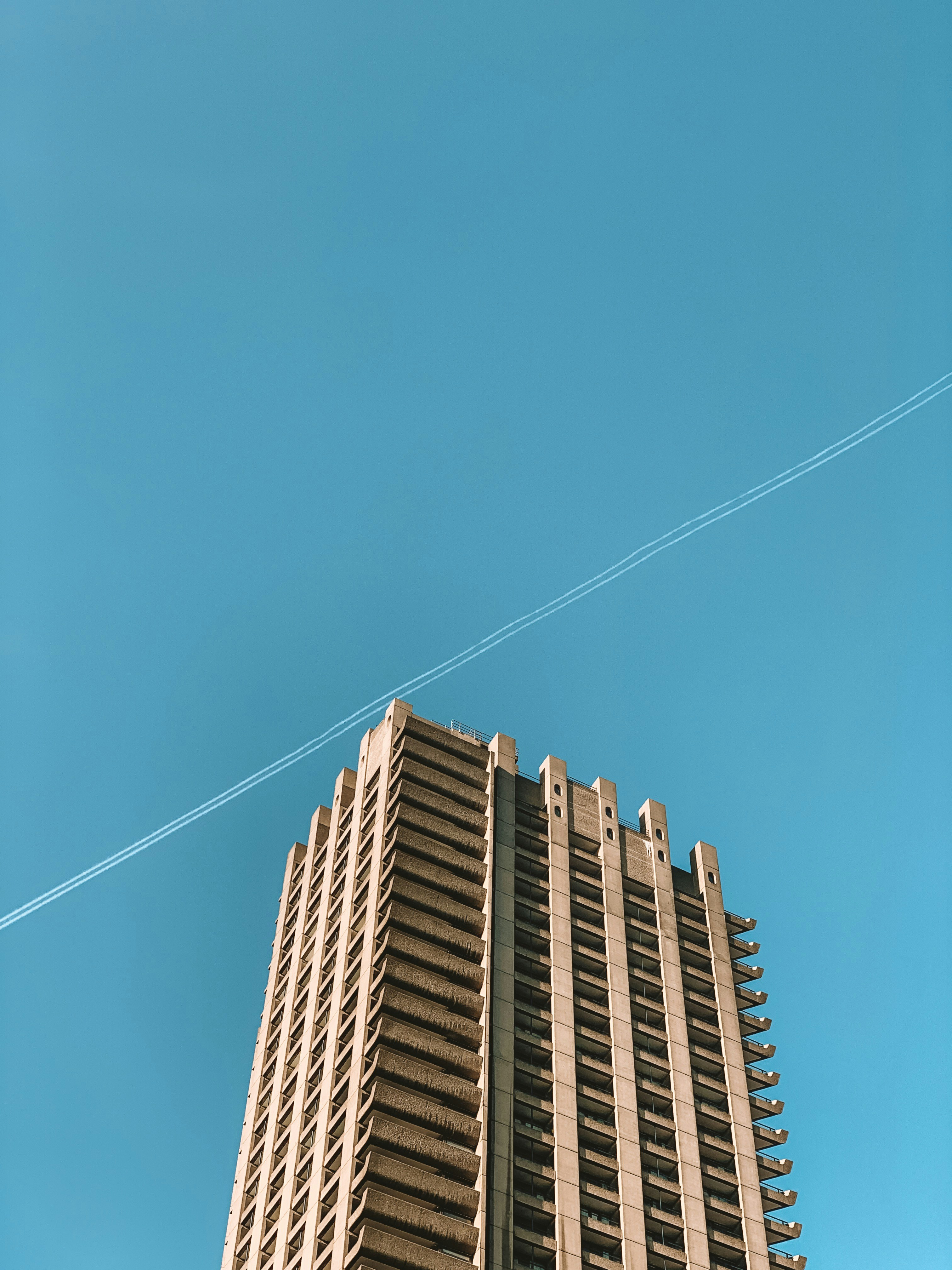 Contrail above high-rise building during day photo – Free Building ...