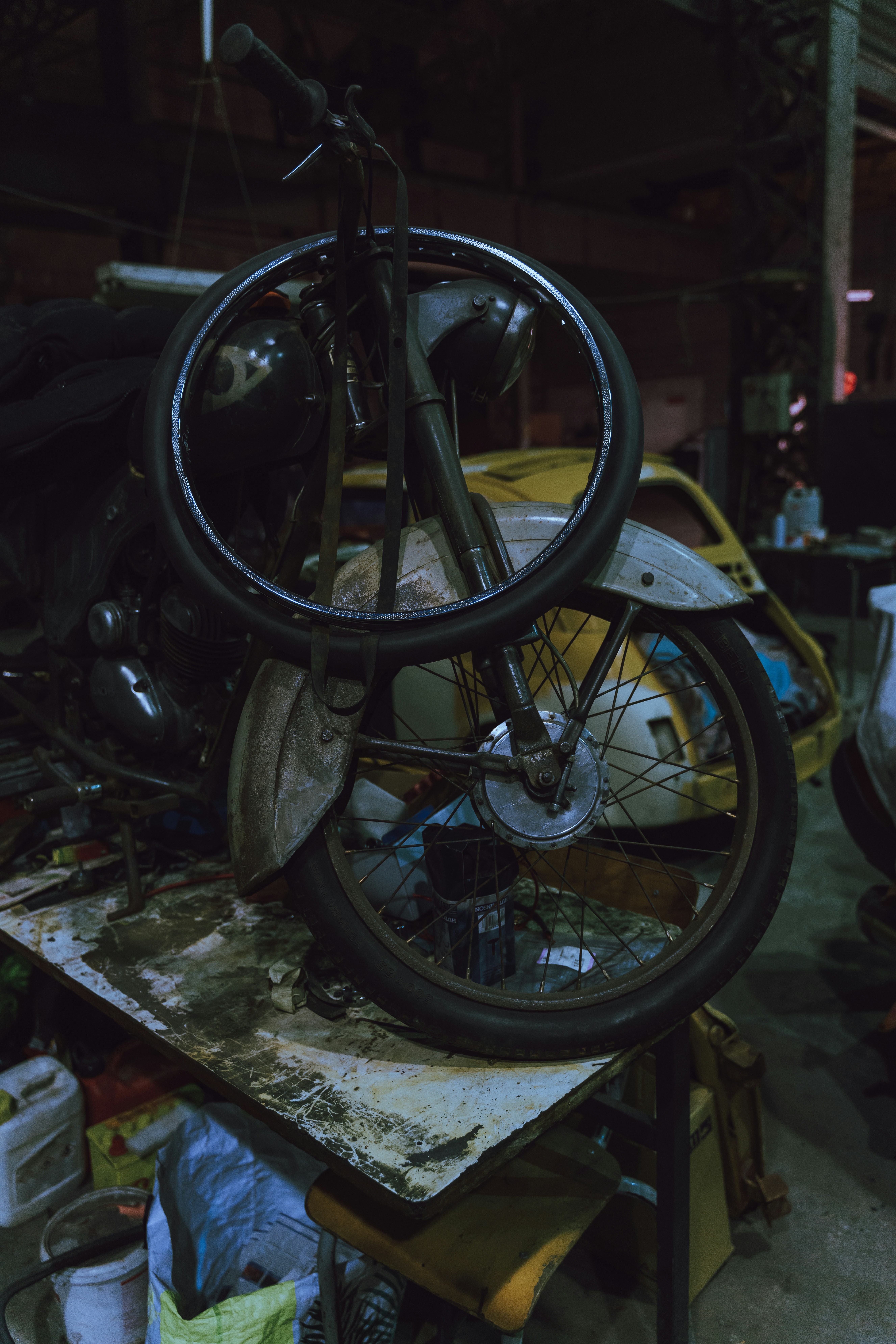 An old motorcycle resting on a cluttered workbench, surrounded by tools and parts, showcasing the charm of a mechanic's workshop.