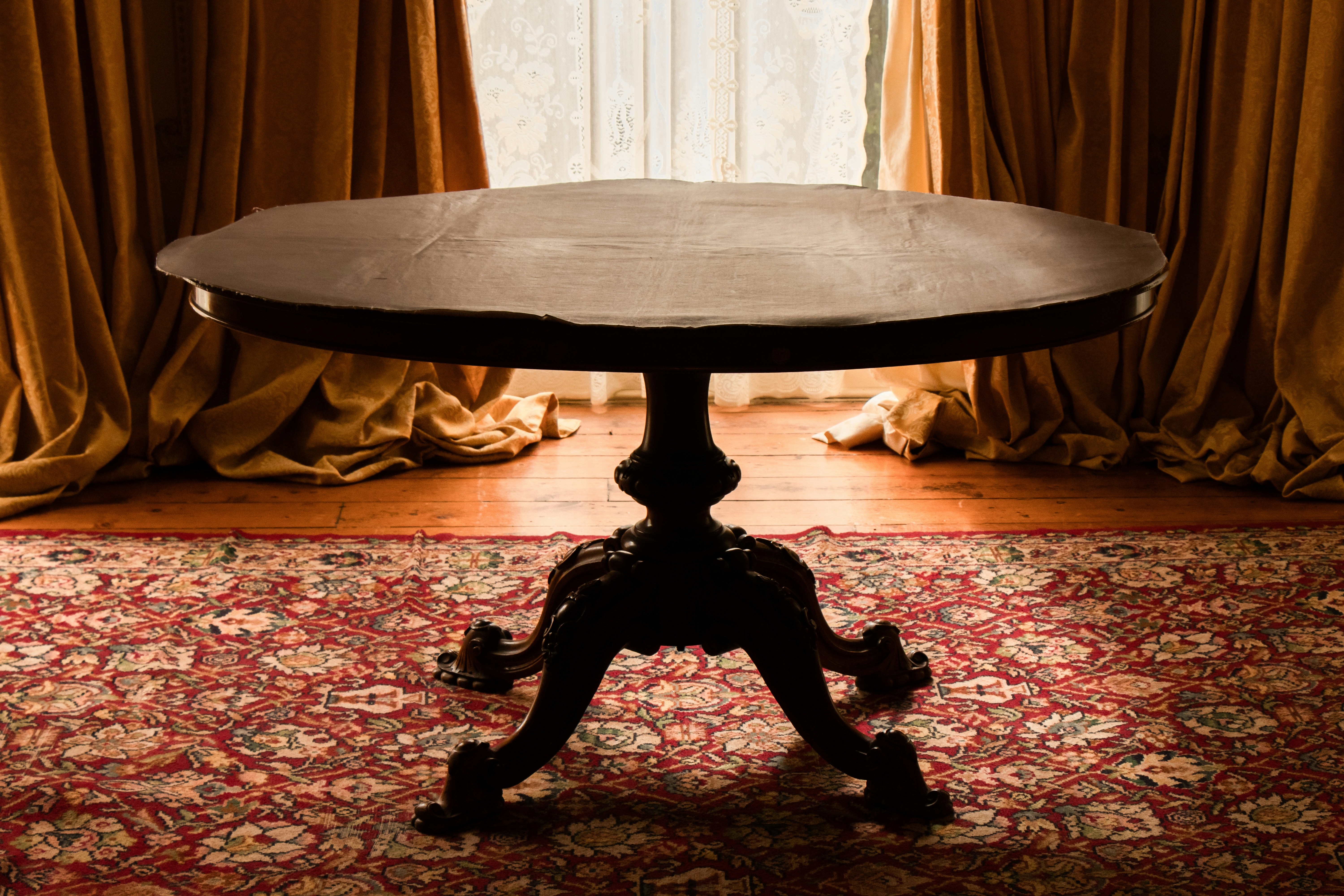 Intricately carved wooden table centered on an ornate rug, bathed in soft natural light from a nearby window.
